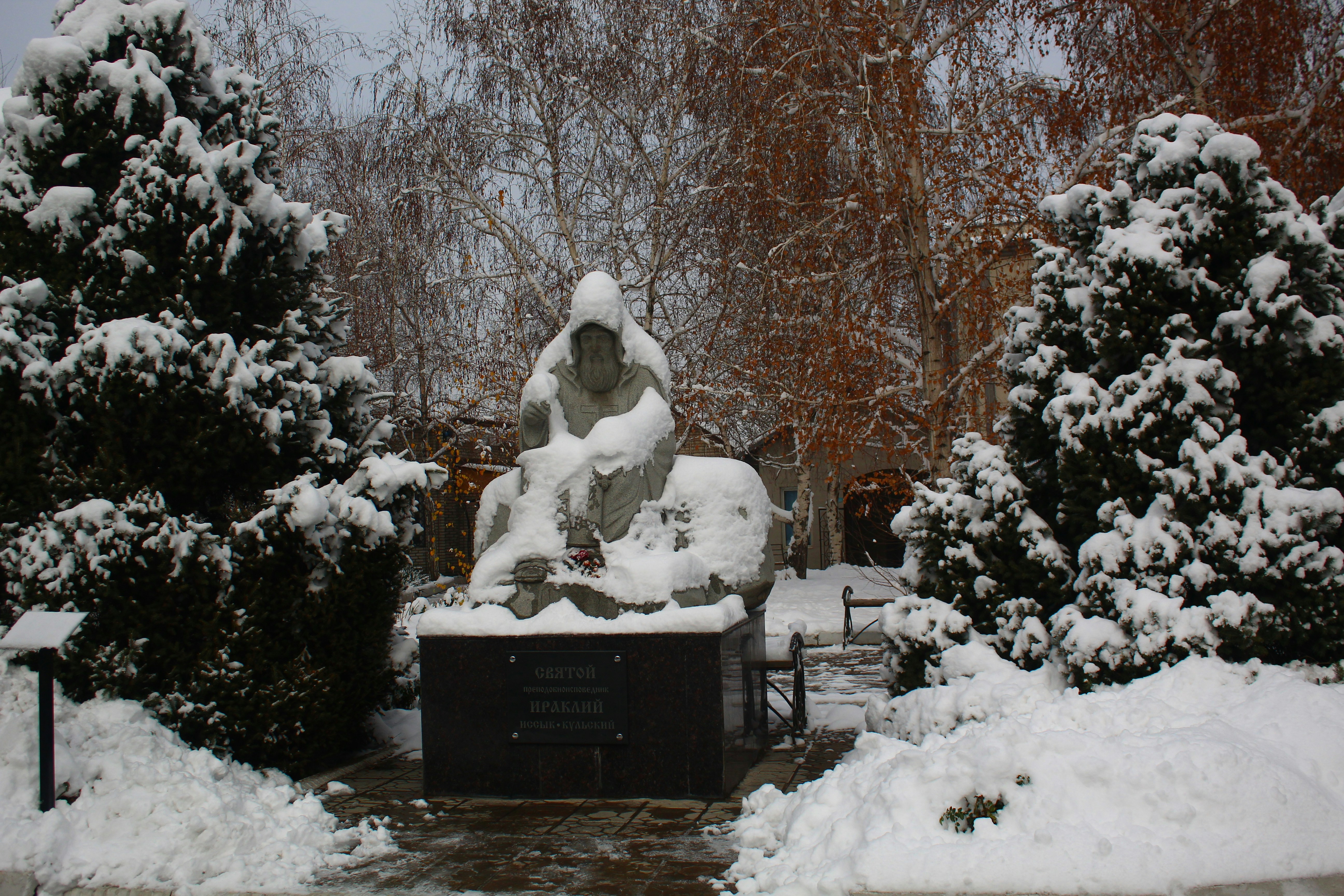 Winter's Silent Sentinel: Snow-Covered Statue in a Quiet Garden