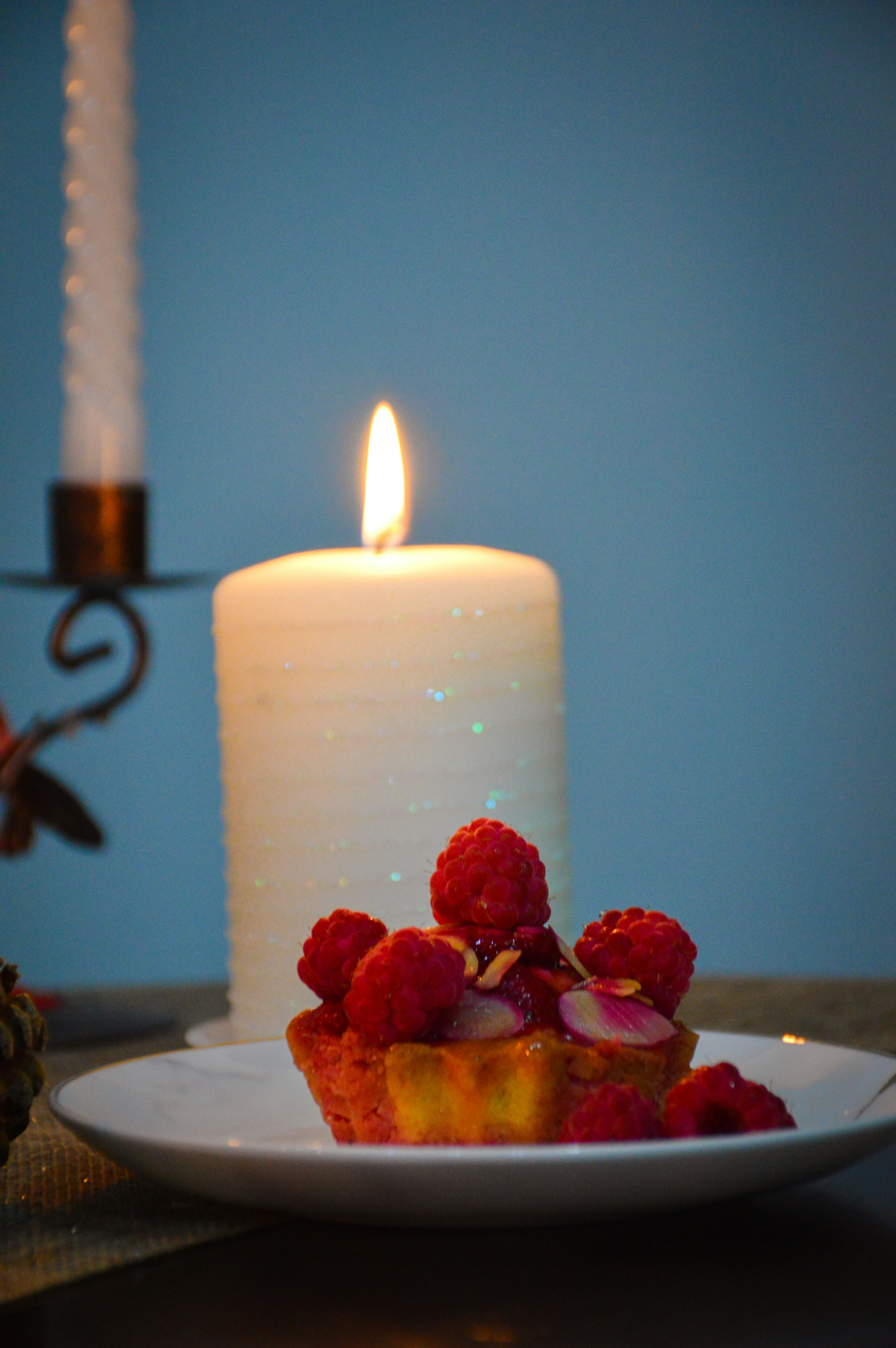 Candlelit Raspberry Tart: Soft Glow on a Blue Evening Table