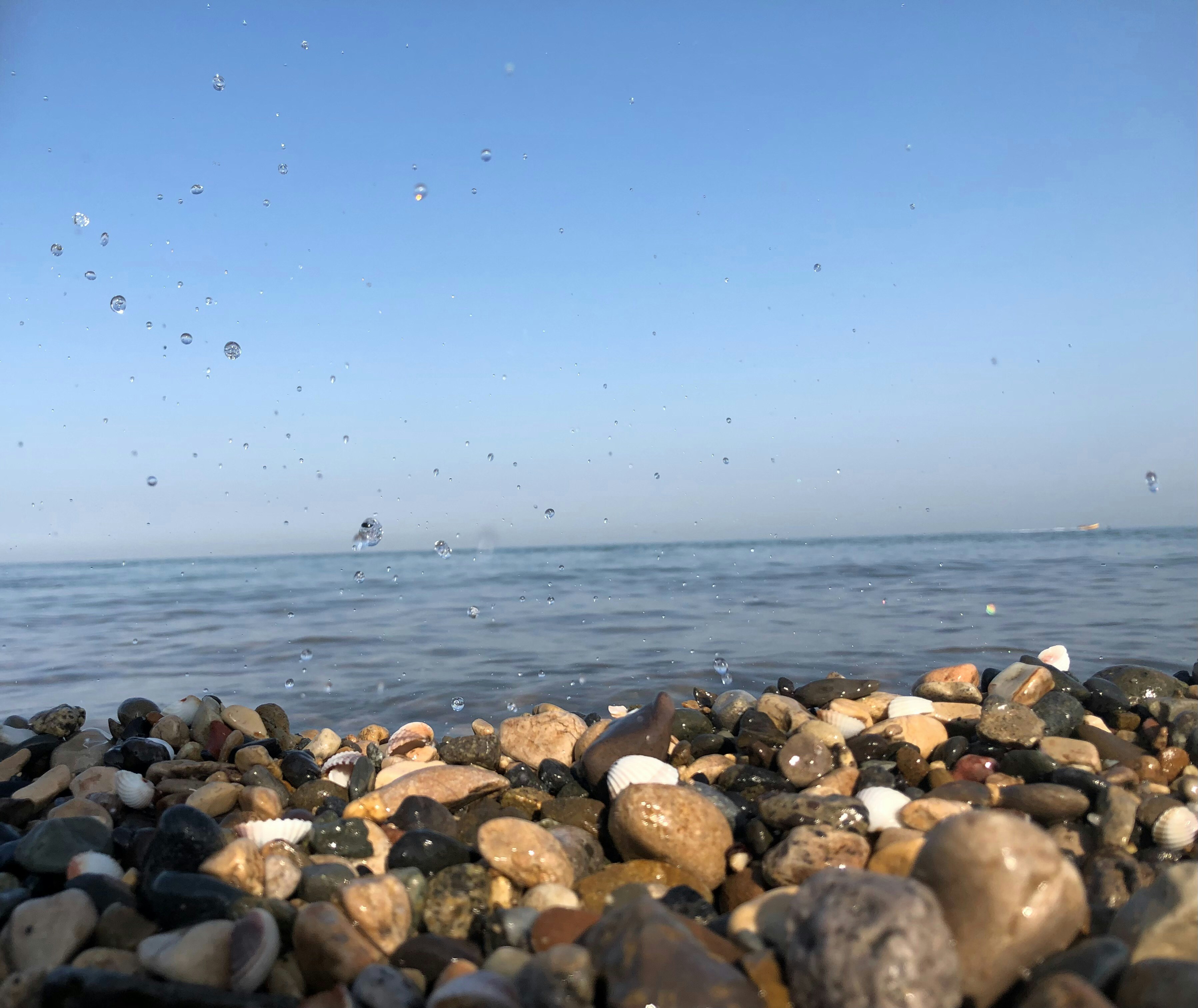 Rocks and pebbles on the shore of a body of water photo – Free Beach ...