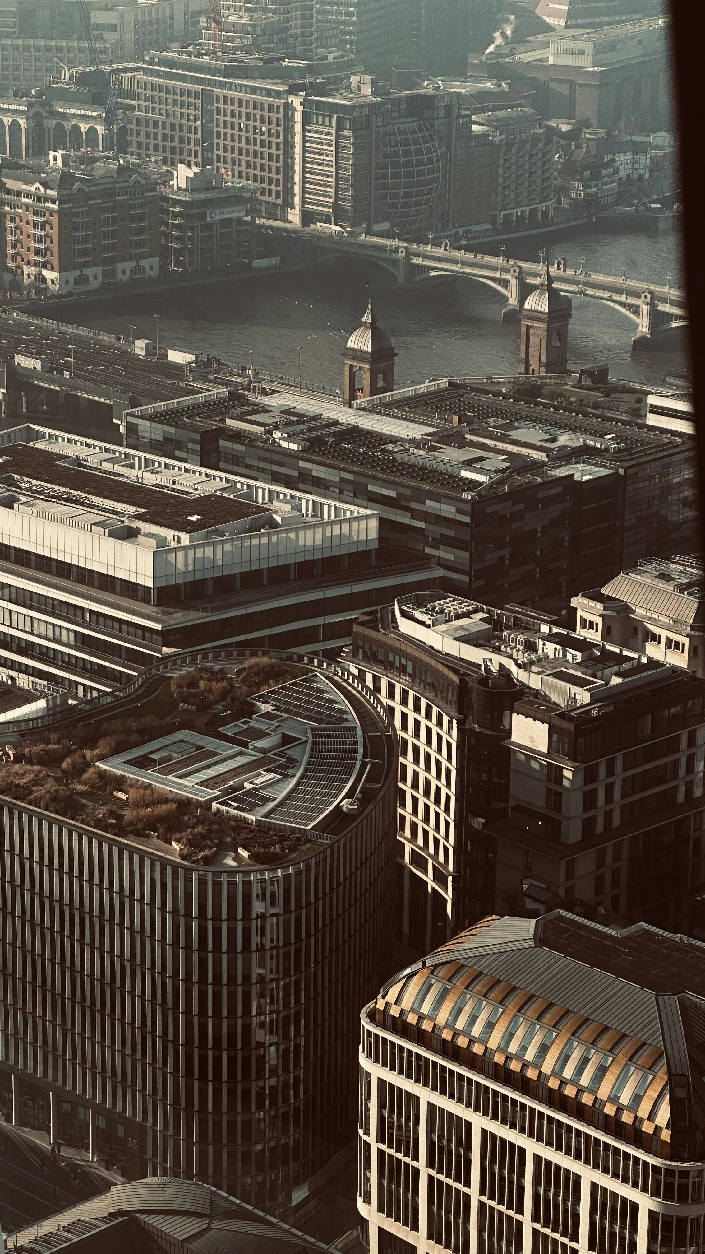 Aerial view showcasing a blend of modern buildings and historical architecture along the river, highlighting the intricate urban landscape.