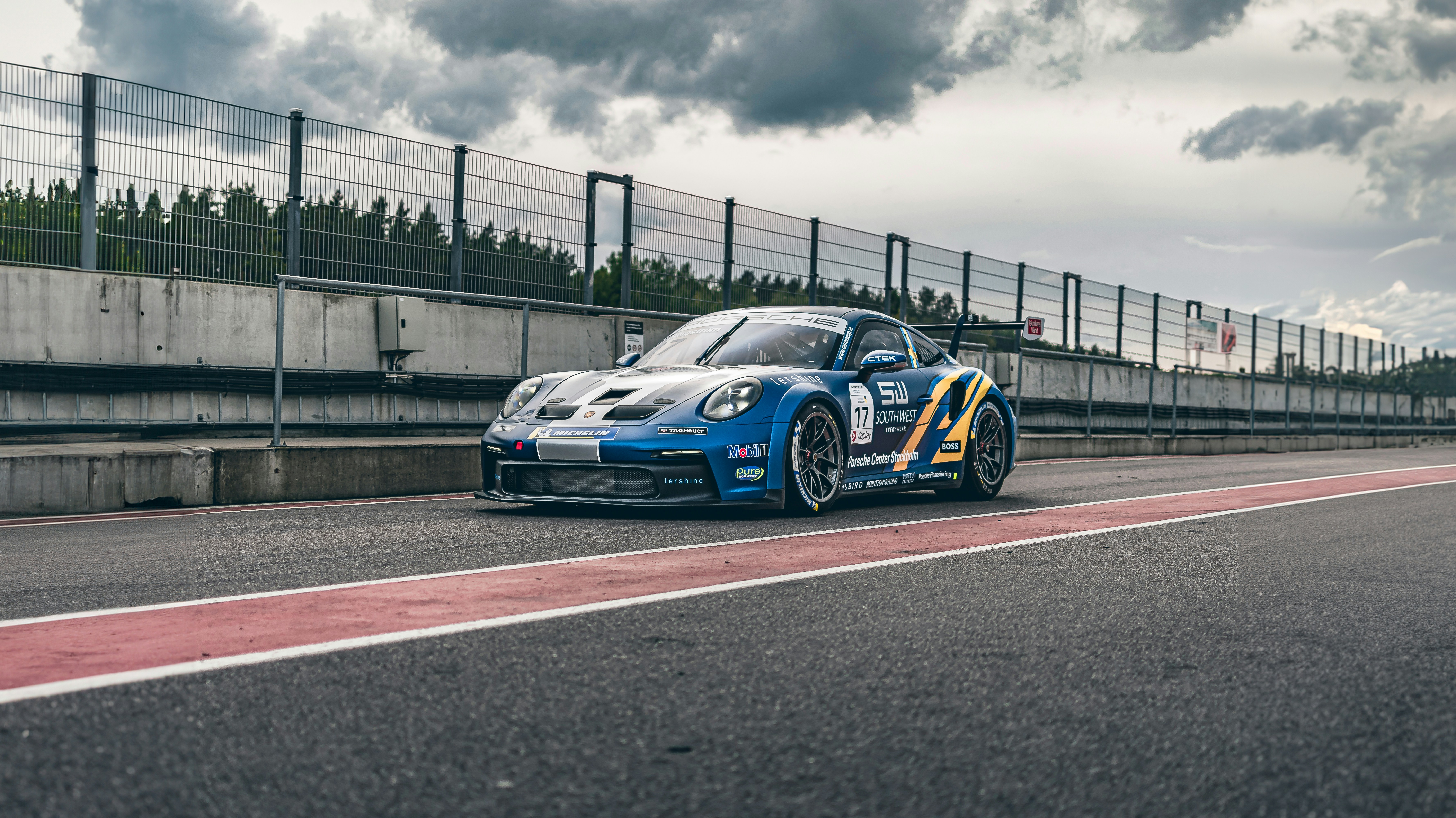 A blue race car driving down a race track photo – Free Car Image on ...