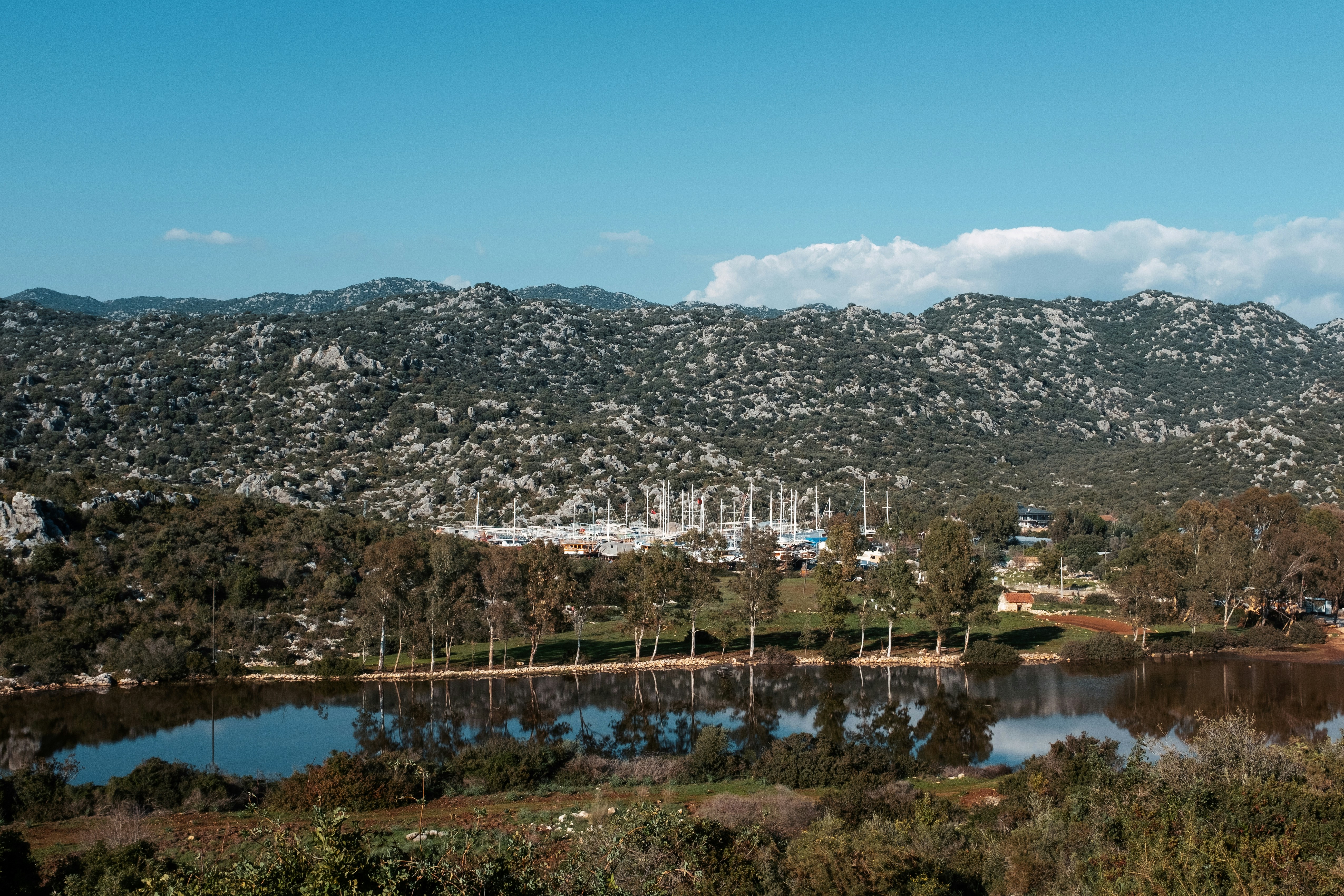 Harbor in the Hills: Sailboats Rest by a Reflective Lake Under a Clear Sky