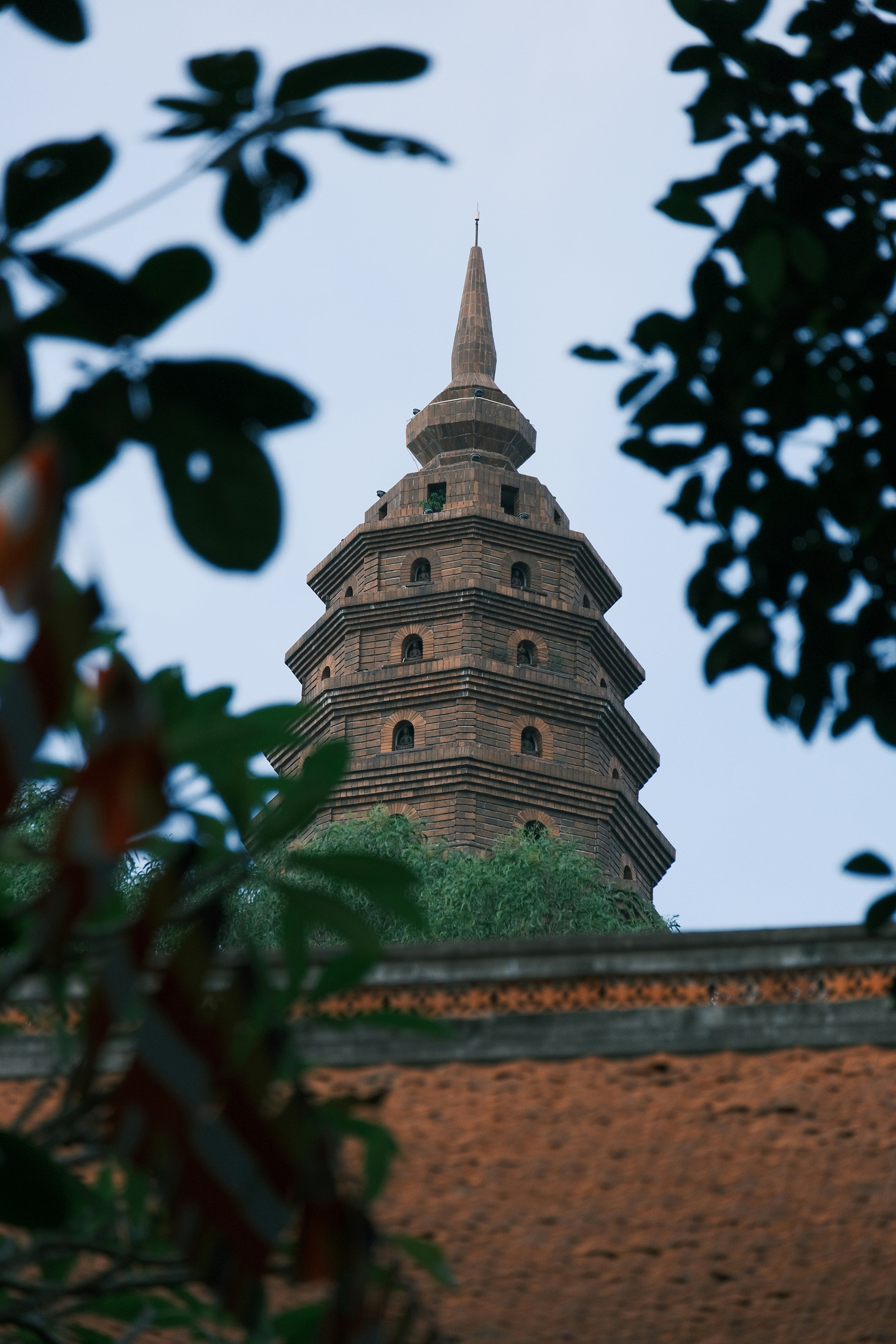 Framed Ascent: The Brick Pagoda Pierces a Quiet Foliage Frame