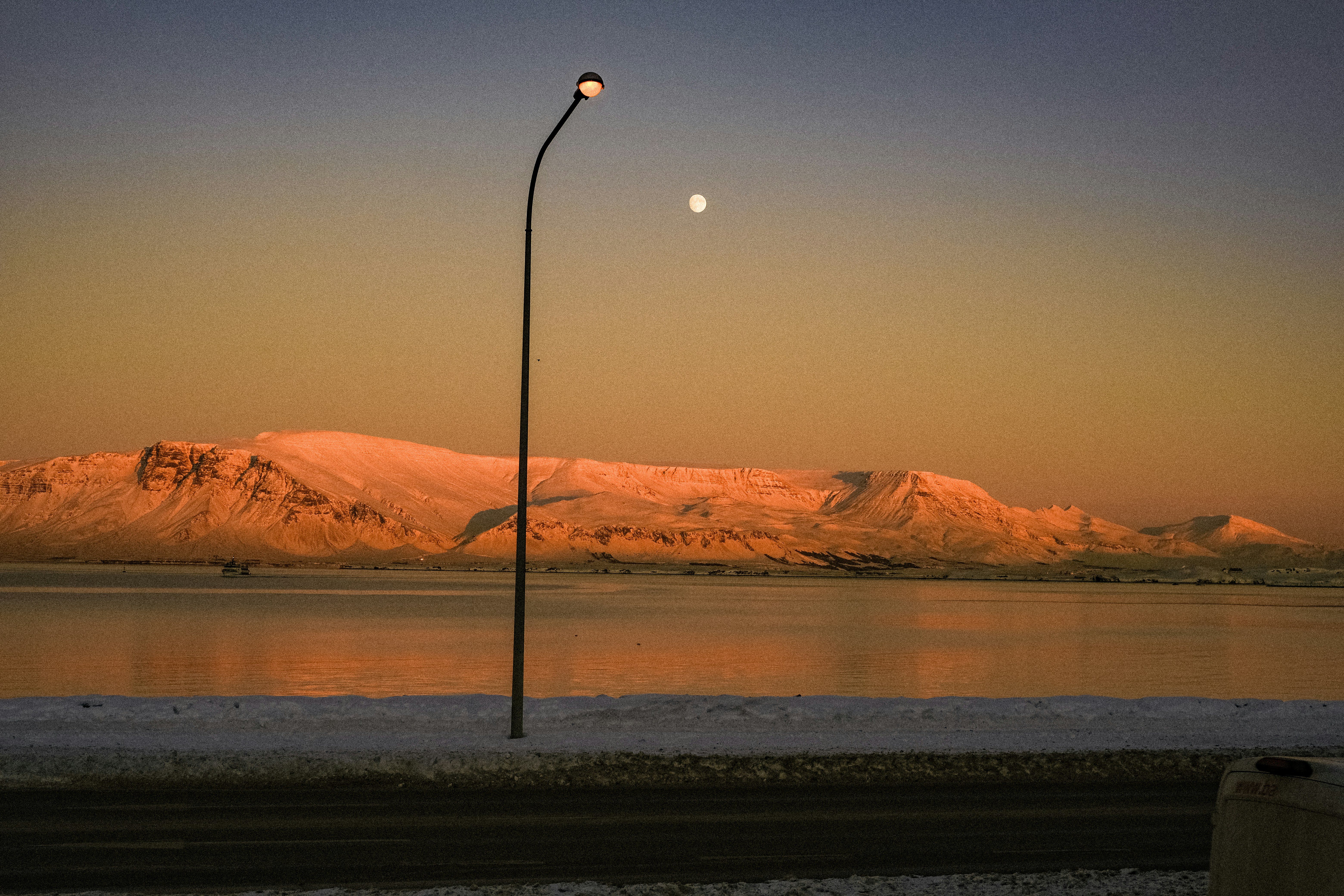Lone Streetlamp Over a Snow-Cloaked Lake at Sunset