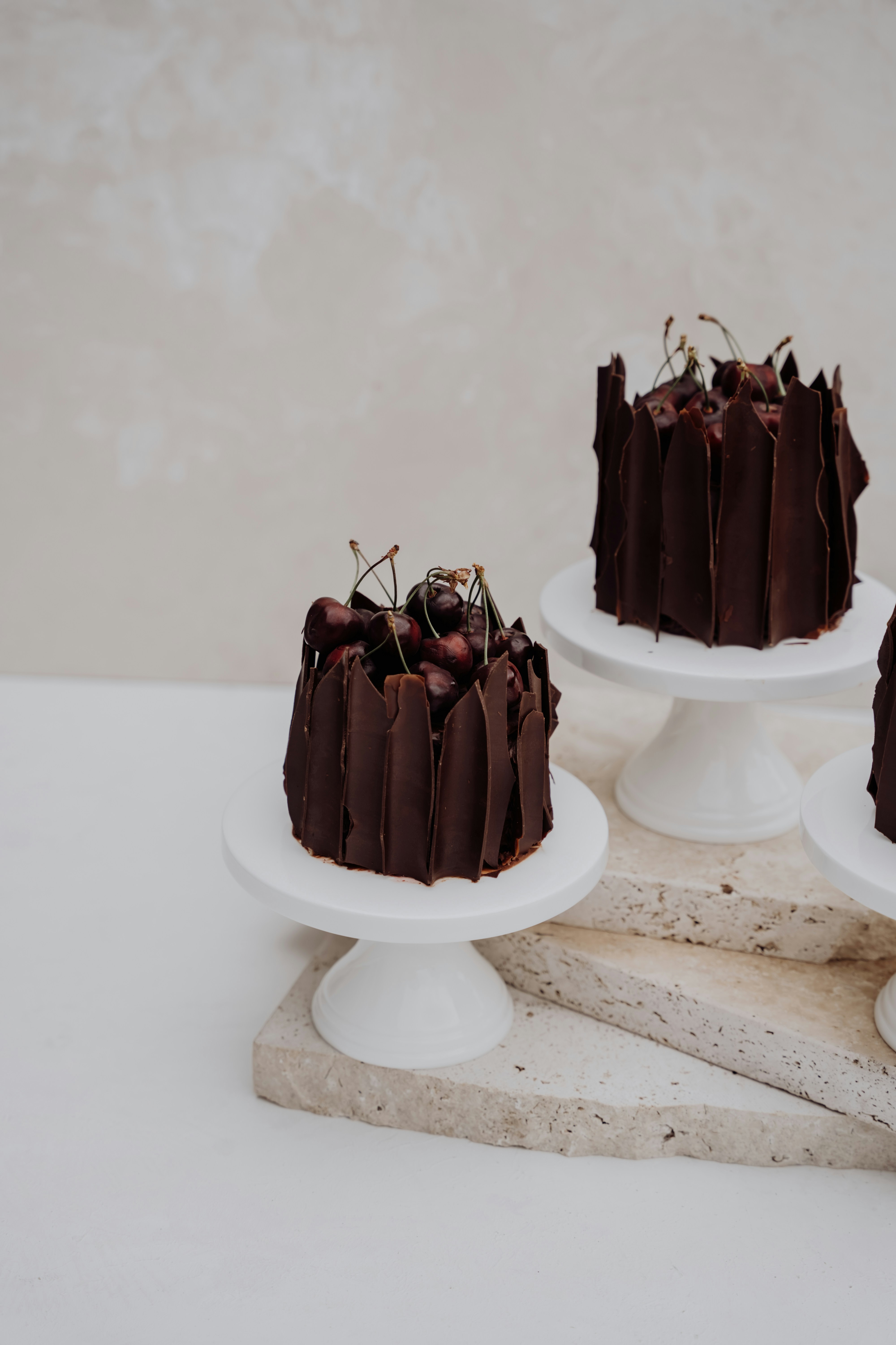Dark Chocolate Towers with Cherry Garnish Rise on White Pedestals