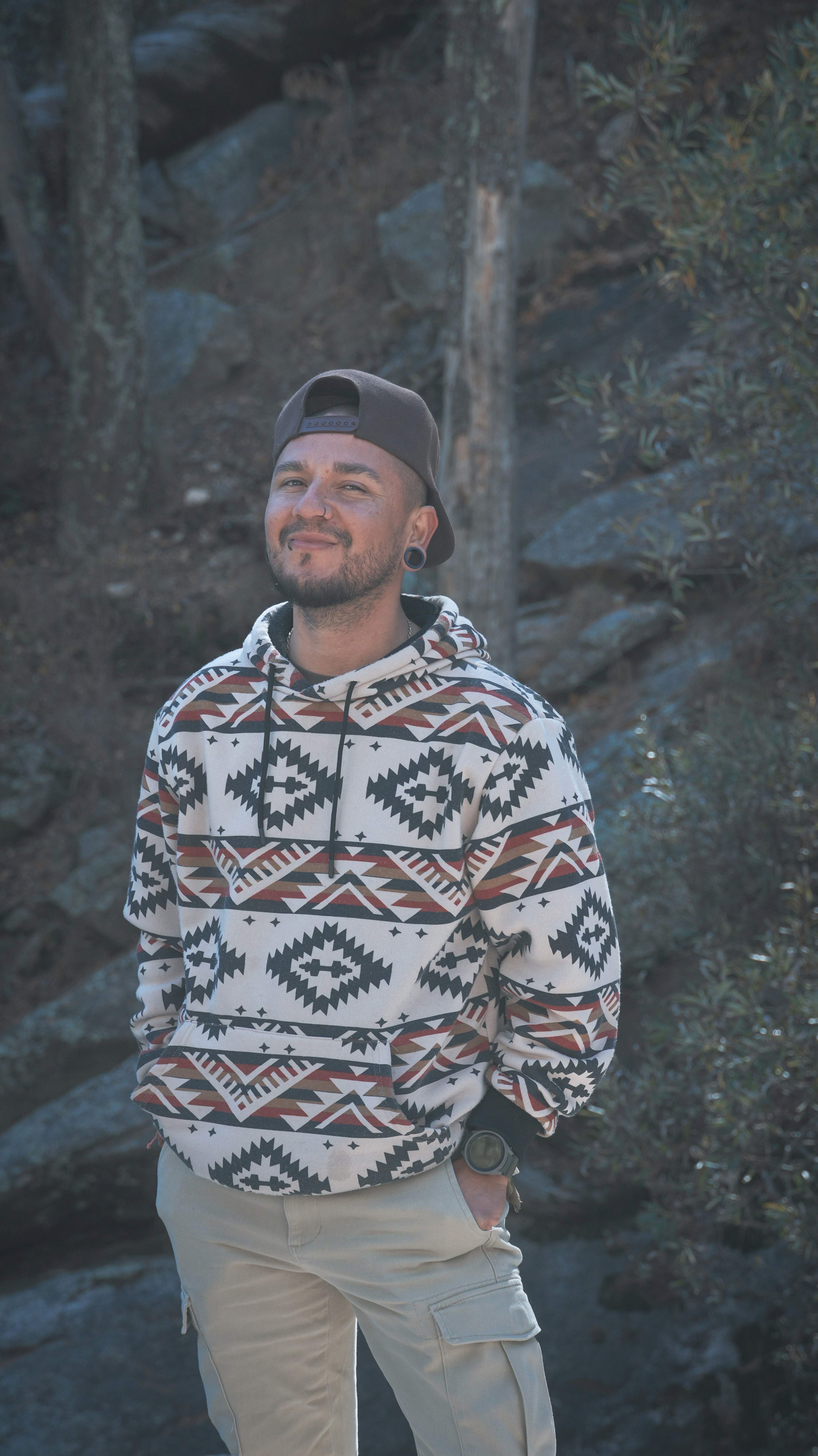 Portrait of a relaxed wanderer in patterned hoodie amid rocky pines