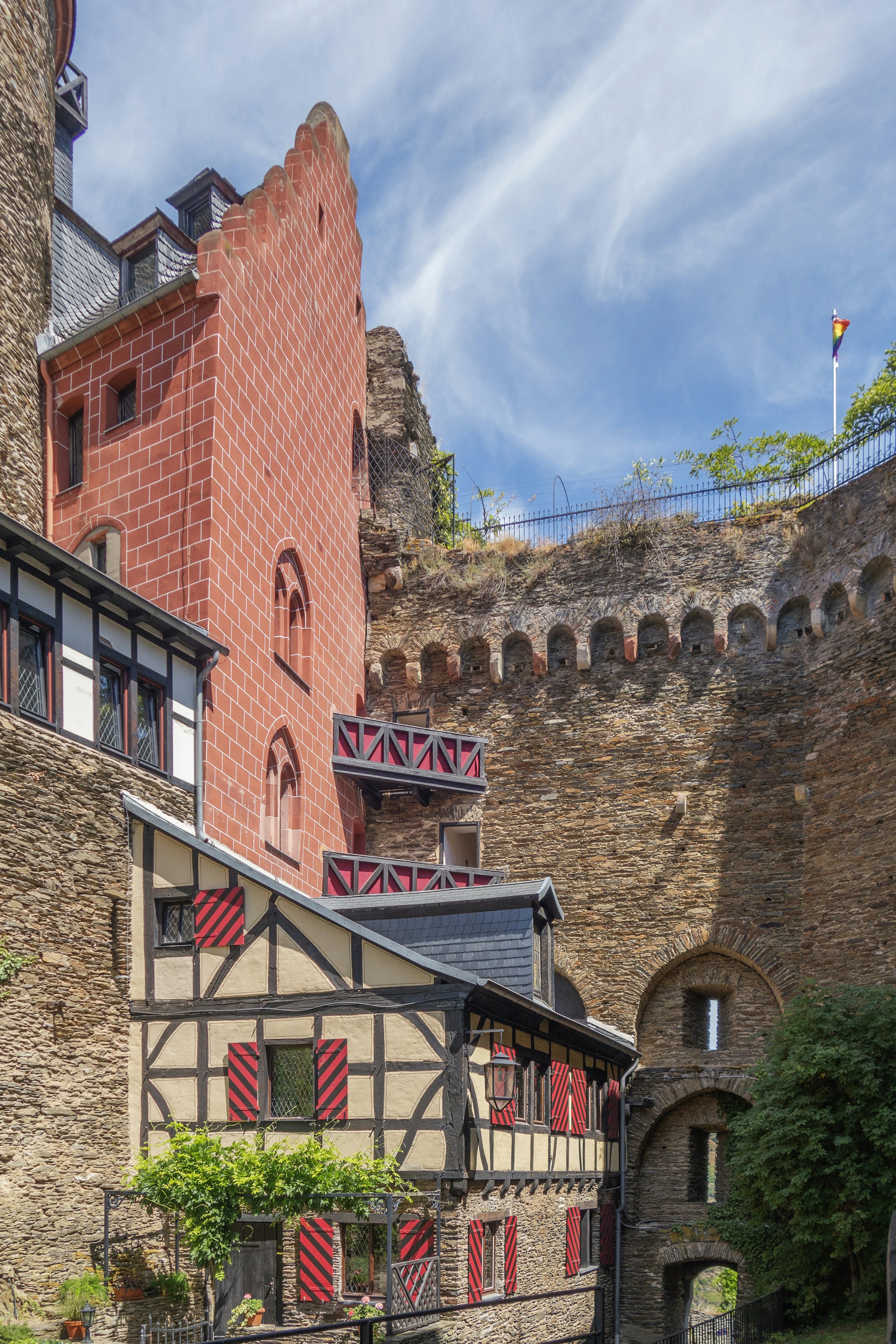 Courtyard of Timber and Stone: Shutters, Arches, and a Fortress Backdrop