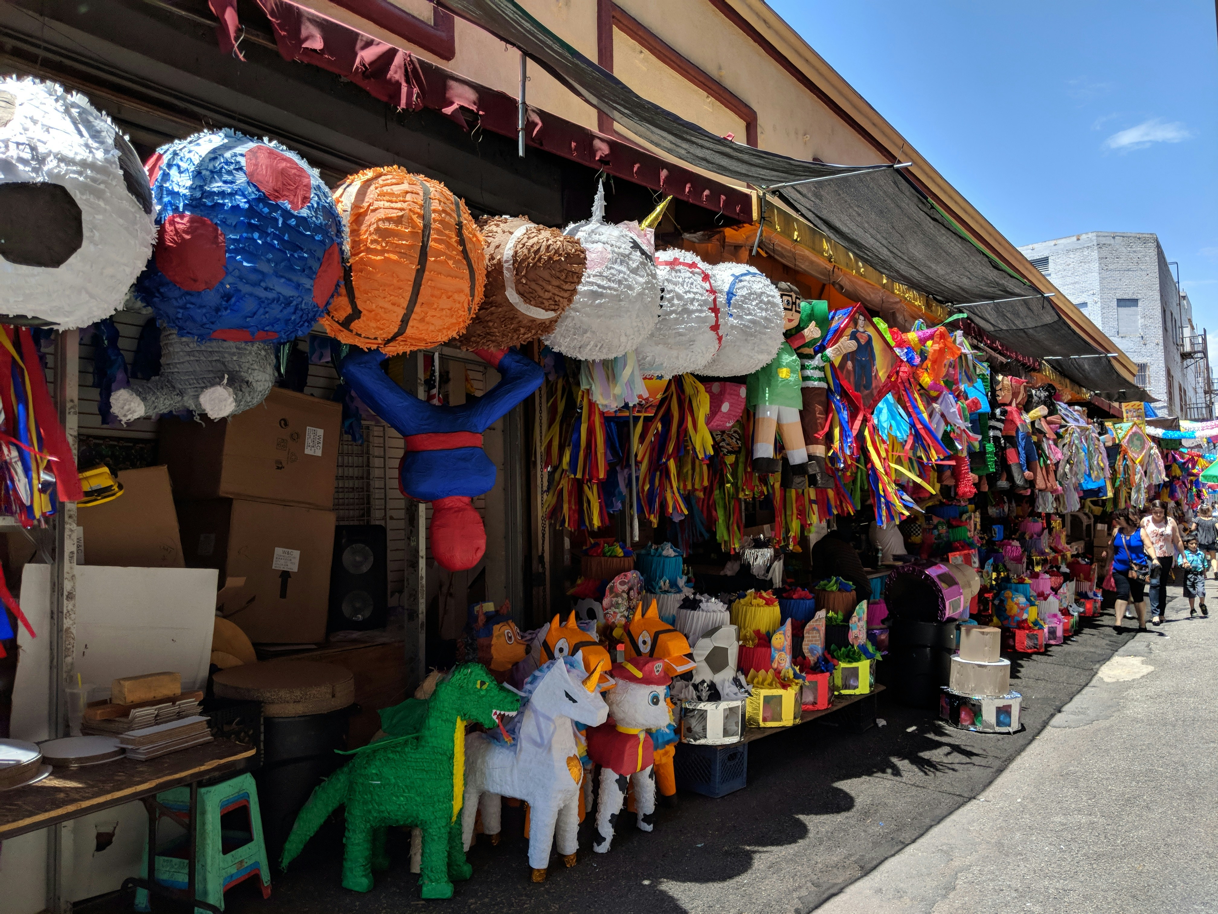 Piñata Row: A Sunlit Street Market of Plush Toys and Colorful Crafts