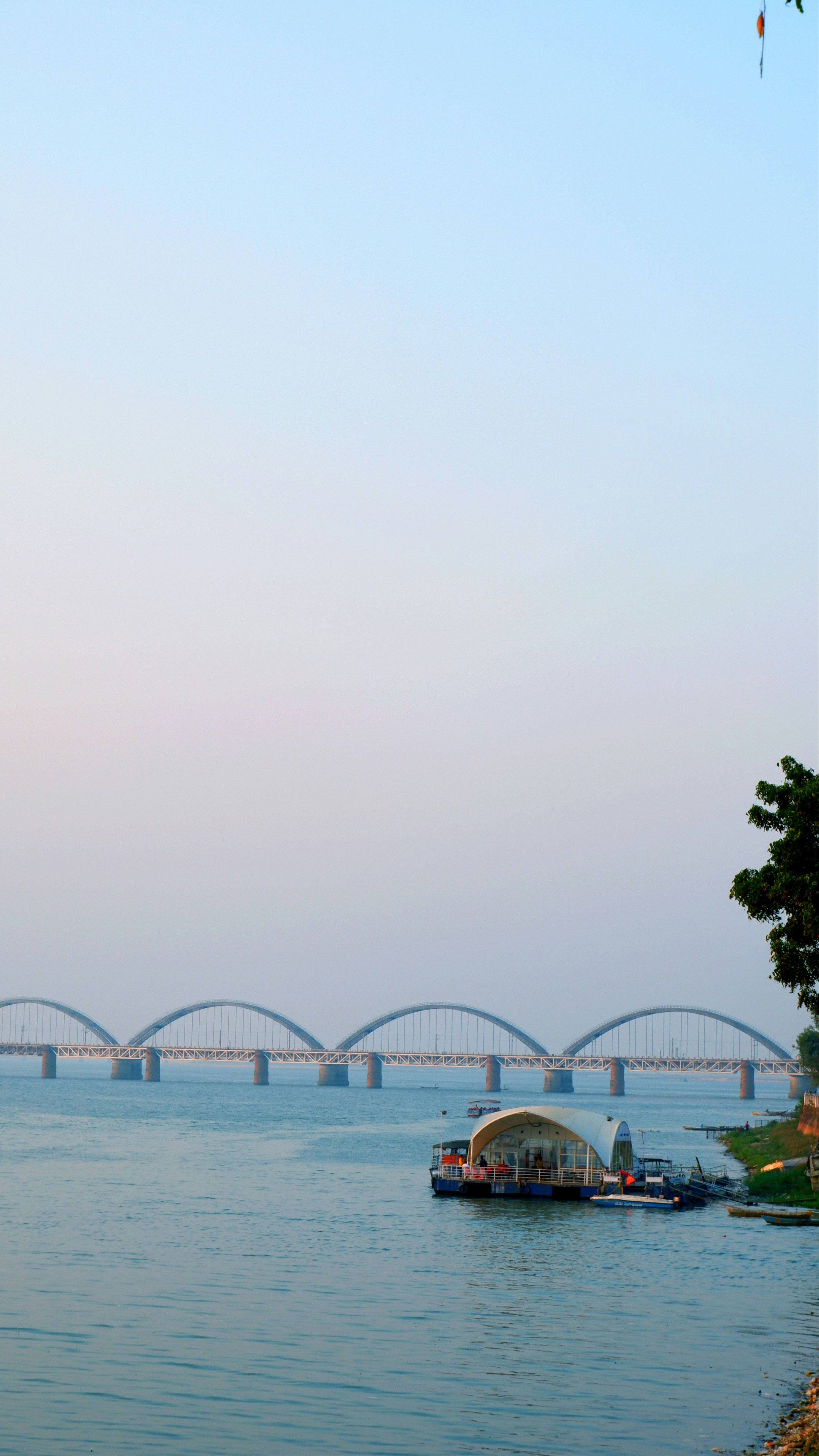 Pastel Dawn Over the River: A Docked Houseboat Beneath the Curved-Arch Bridge