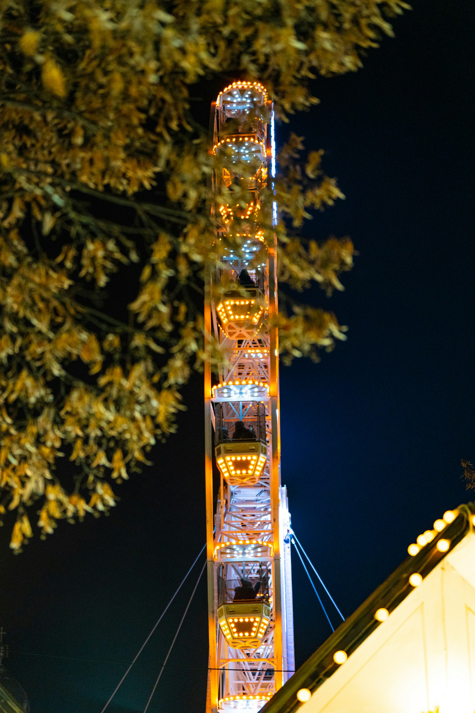 Neon Wheel: Nighttime Ferris Wheel Illuminates a Quiet City Street