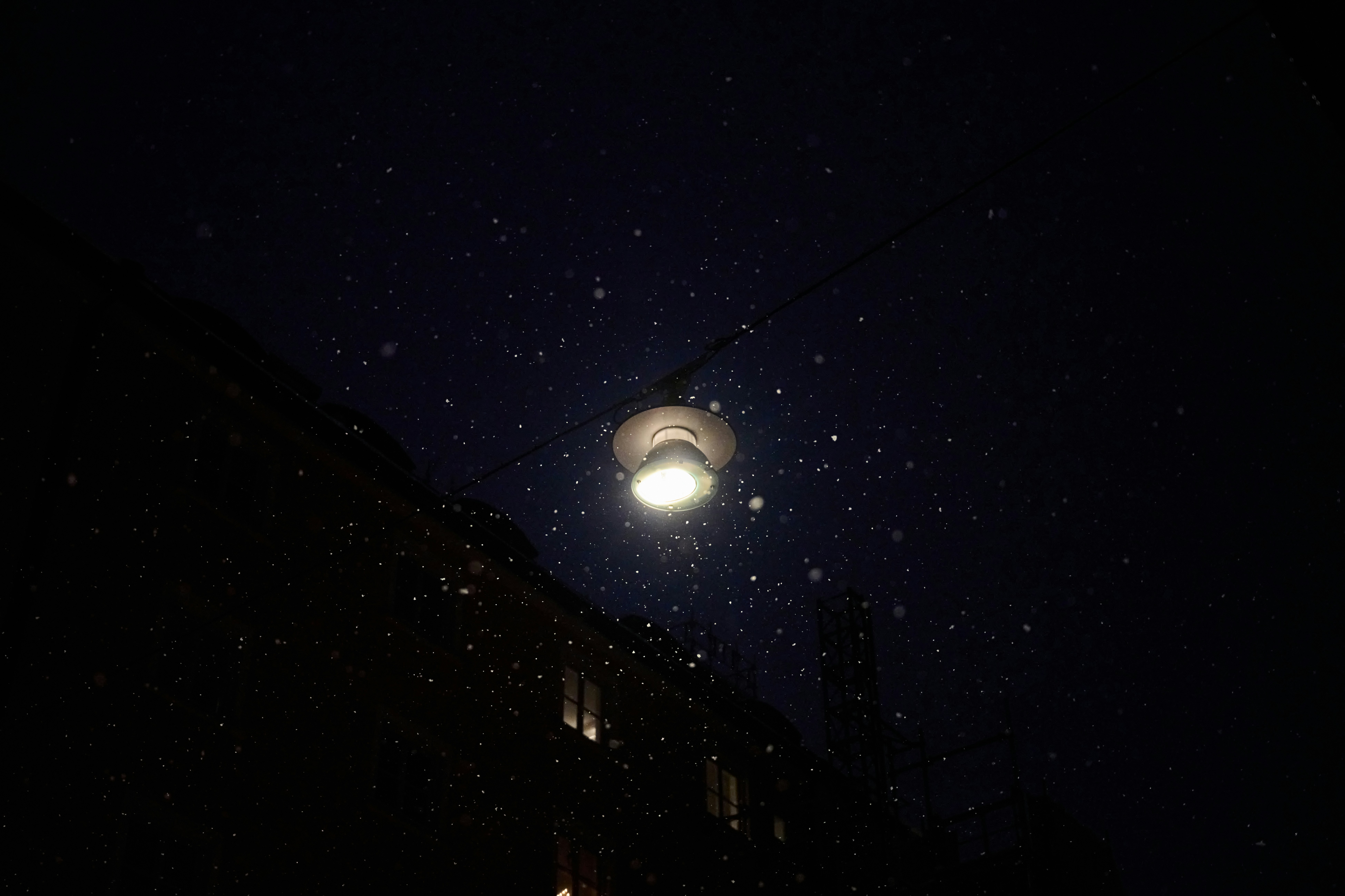 Central Lantern Through a Snowfall Over a Quiet Urban Block