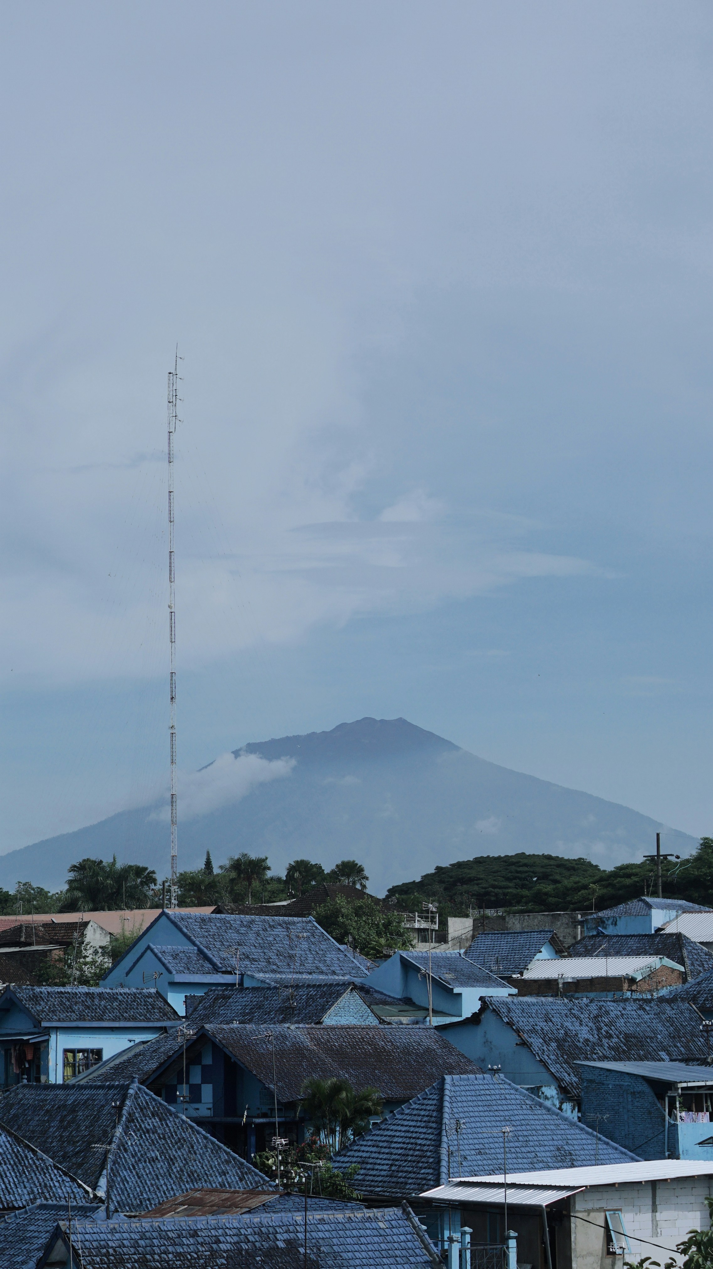 Blue-Tiled Horizon: Rooftops Meet a Distant Volcano Peak