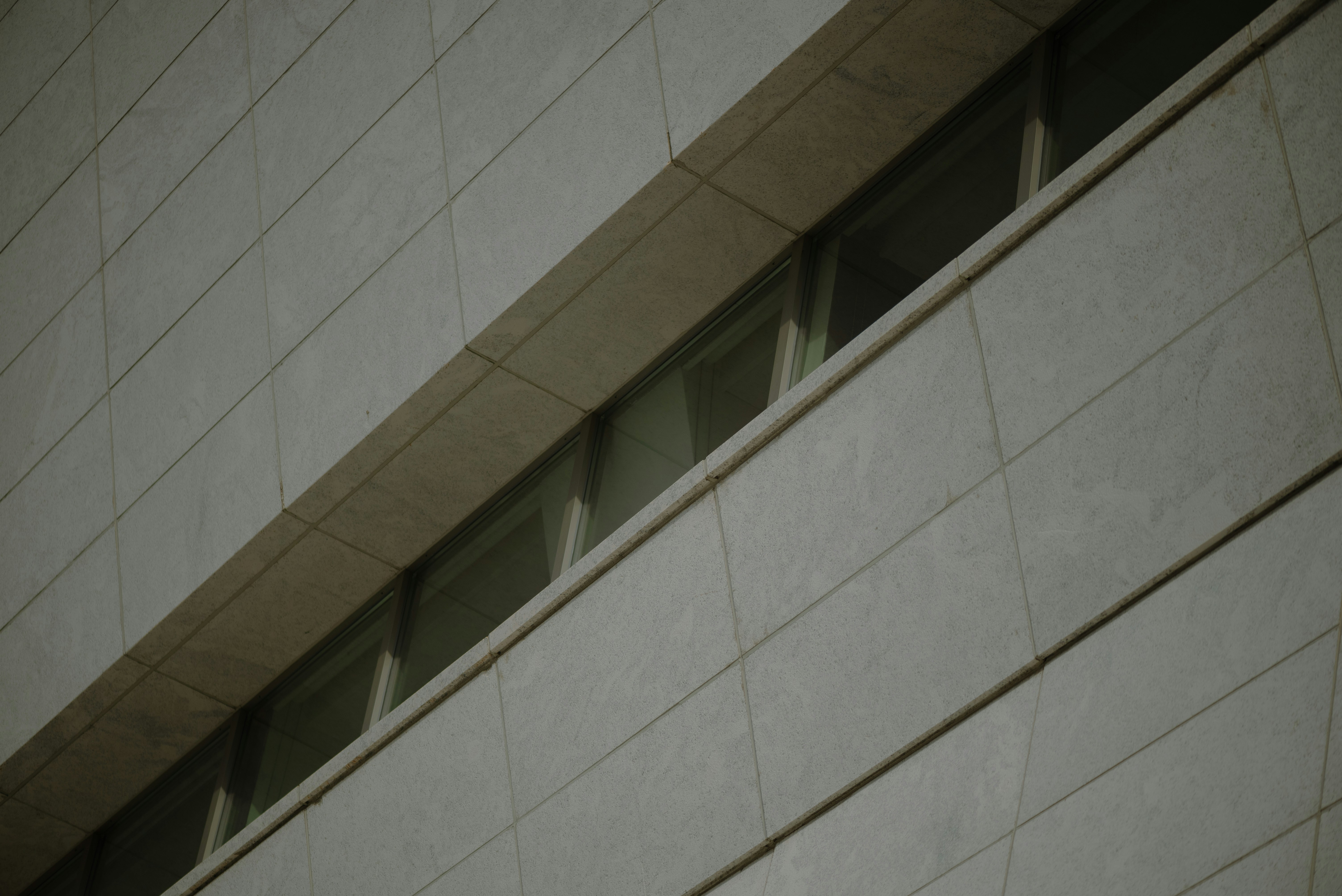 Close-up of a modern building facade with diagonal lines and rectangular windows.