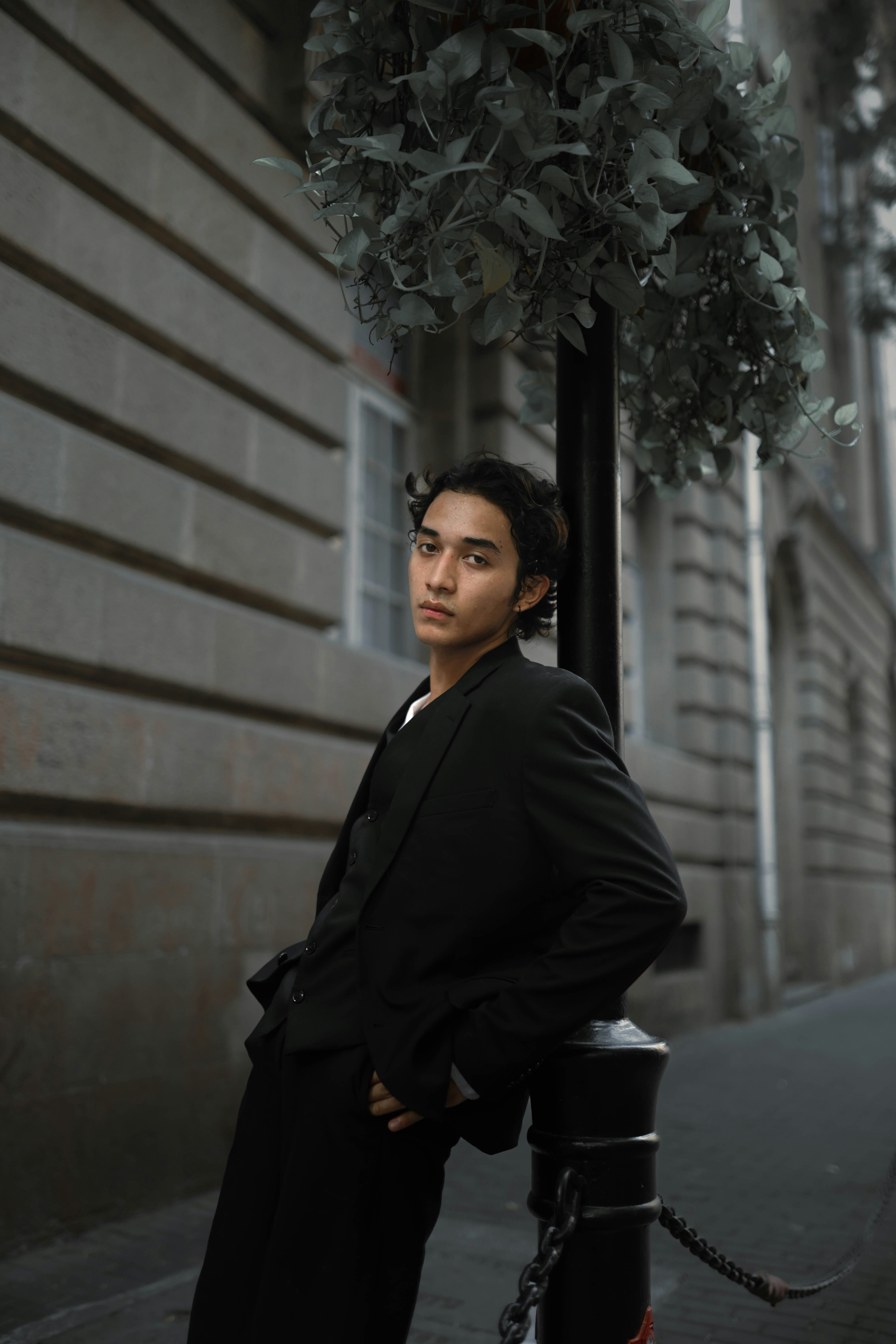 A man in a suit leaning against a pole photo – Free Style Image on Unsplash