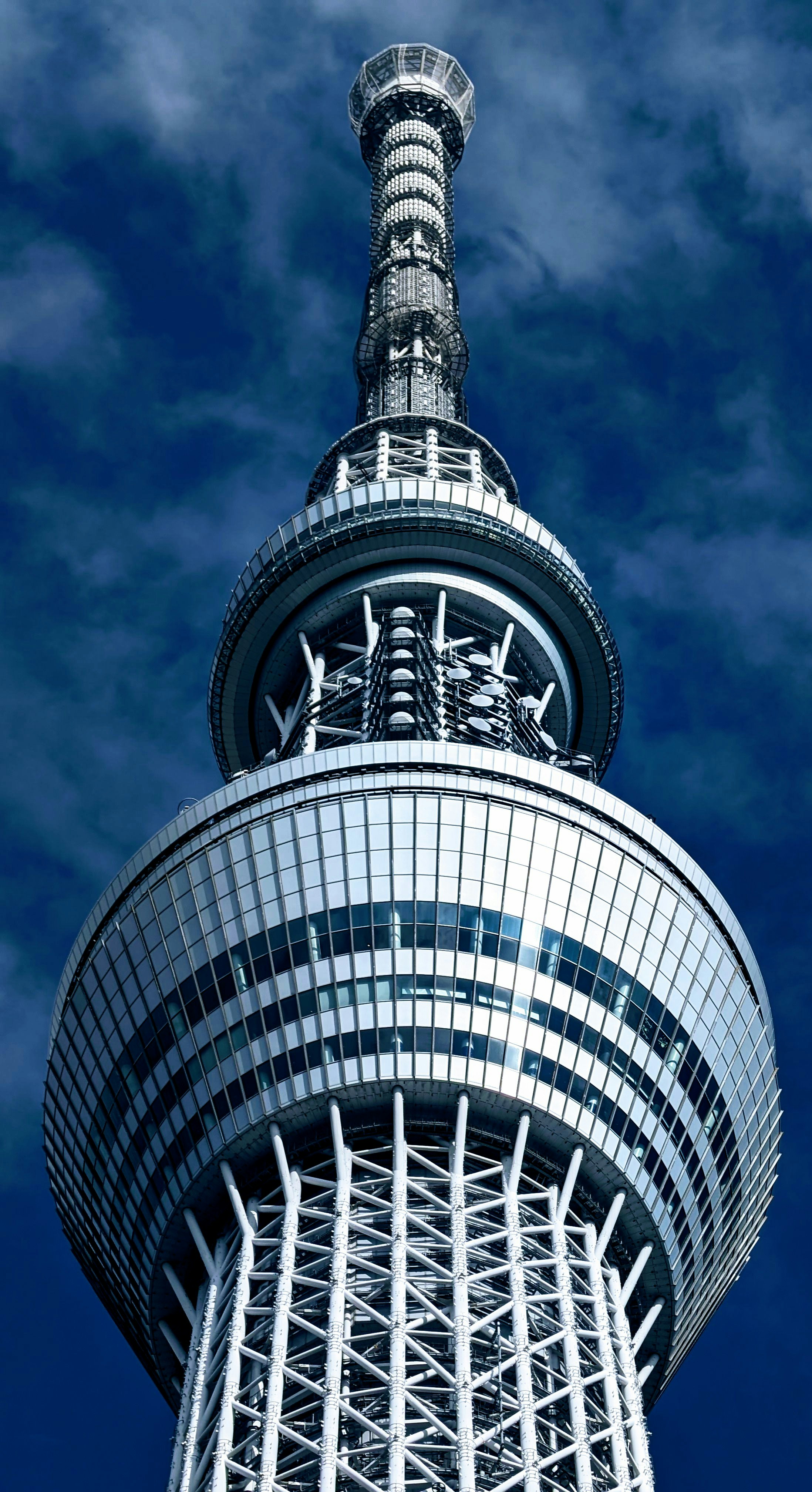 Close-up photograph of a tall lattice tower with a circular glass observation deck rising into a clear blue sky.