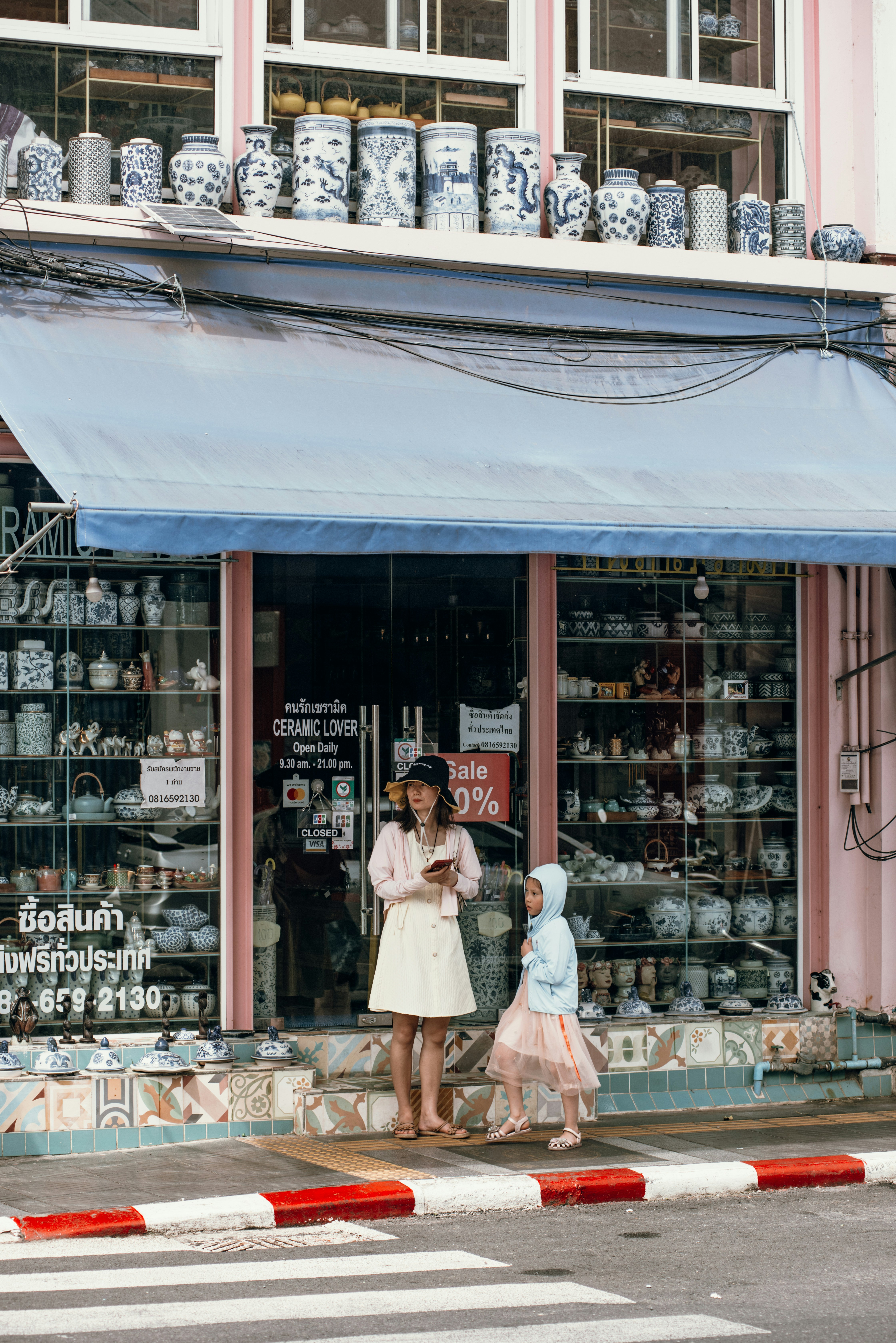 Blue-porcelain Threshold: Quiet Figures by a Ceramics Shopfront