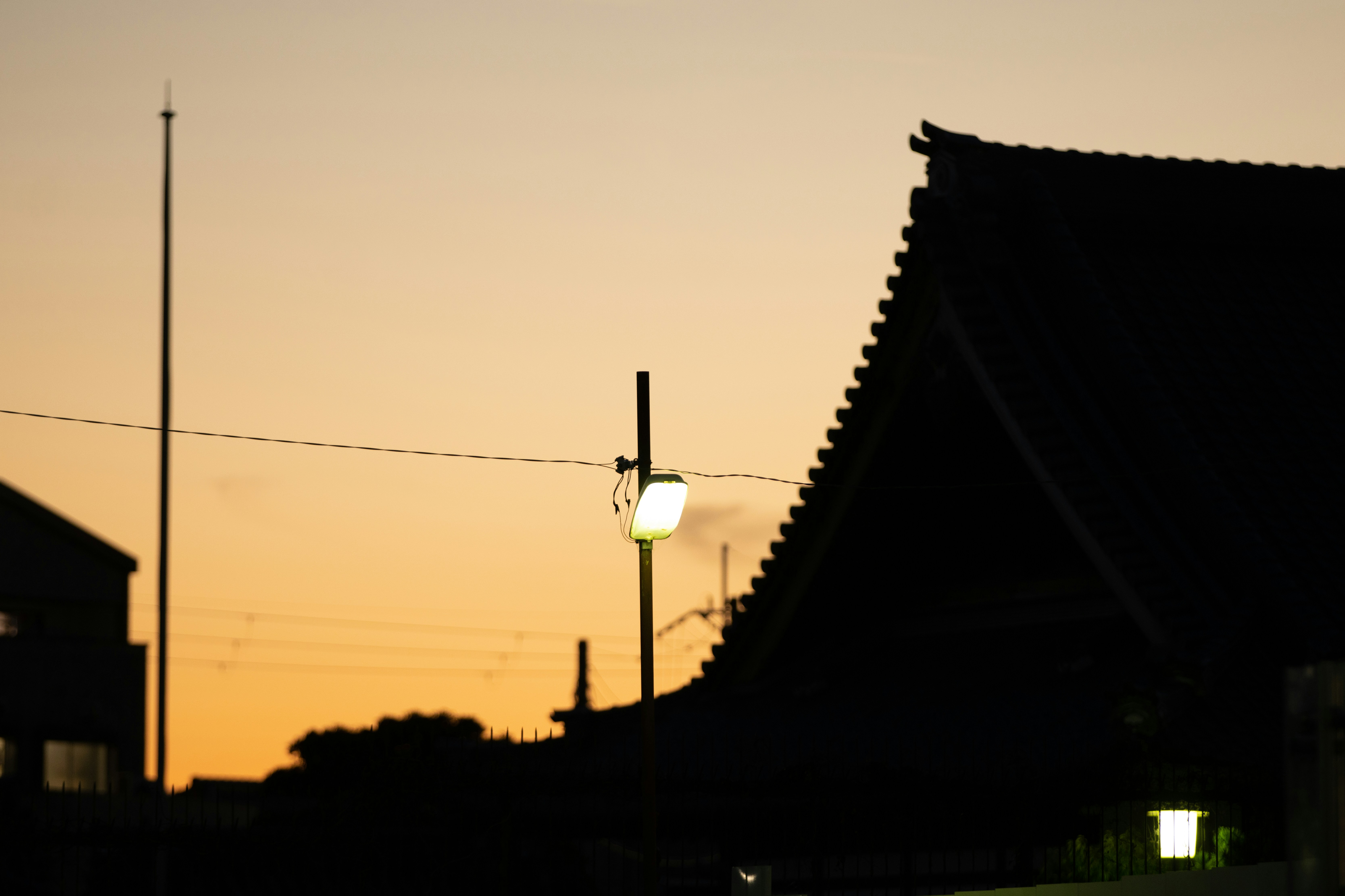 Glow on the Edge: A Streetlamp Before a Temple Silhouette at Sunset
