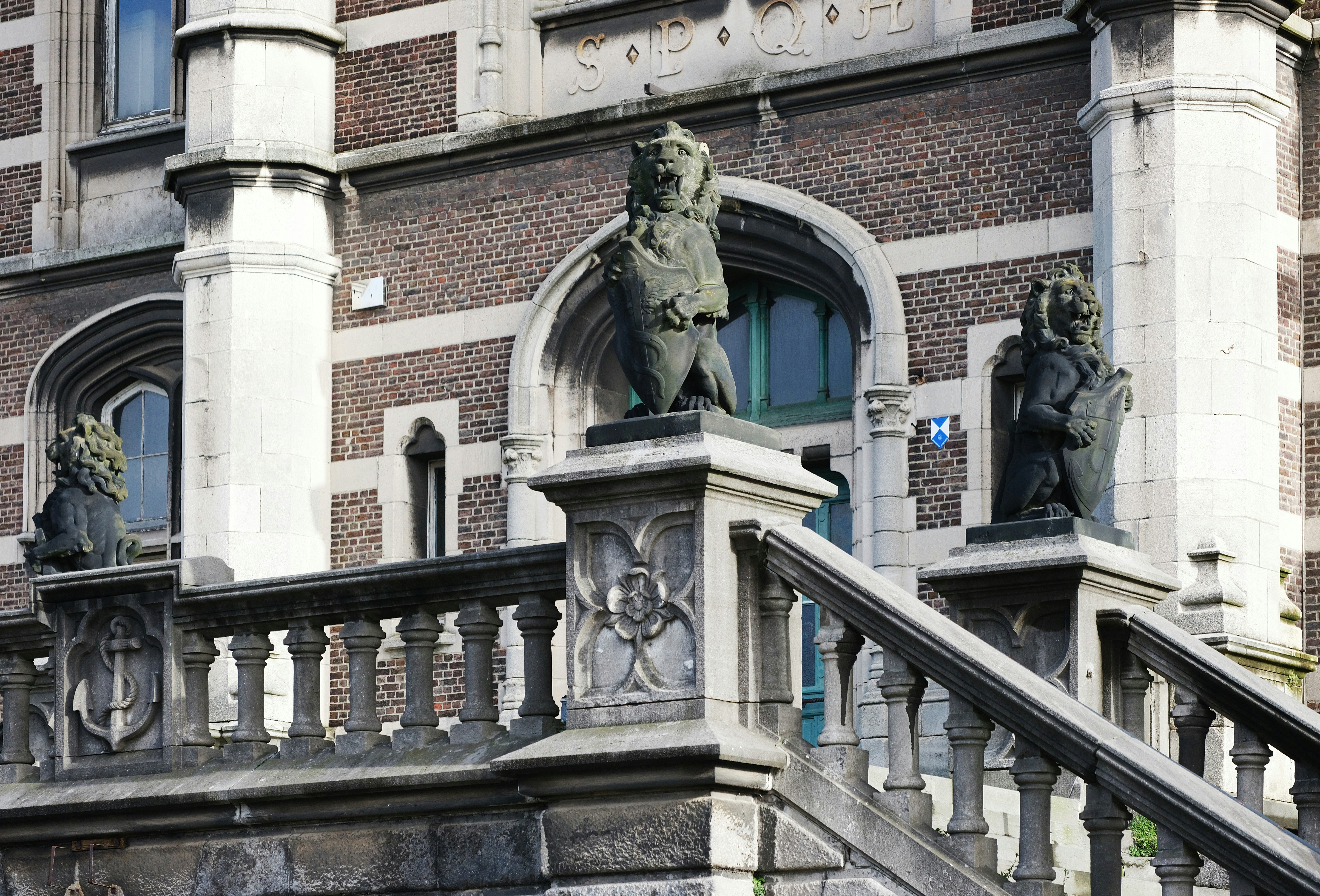Stone statues adorn the steps of a historic brick building in Antwerp.