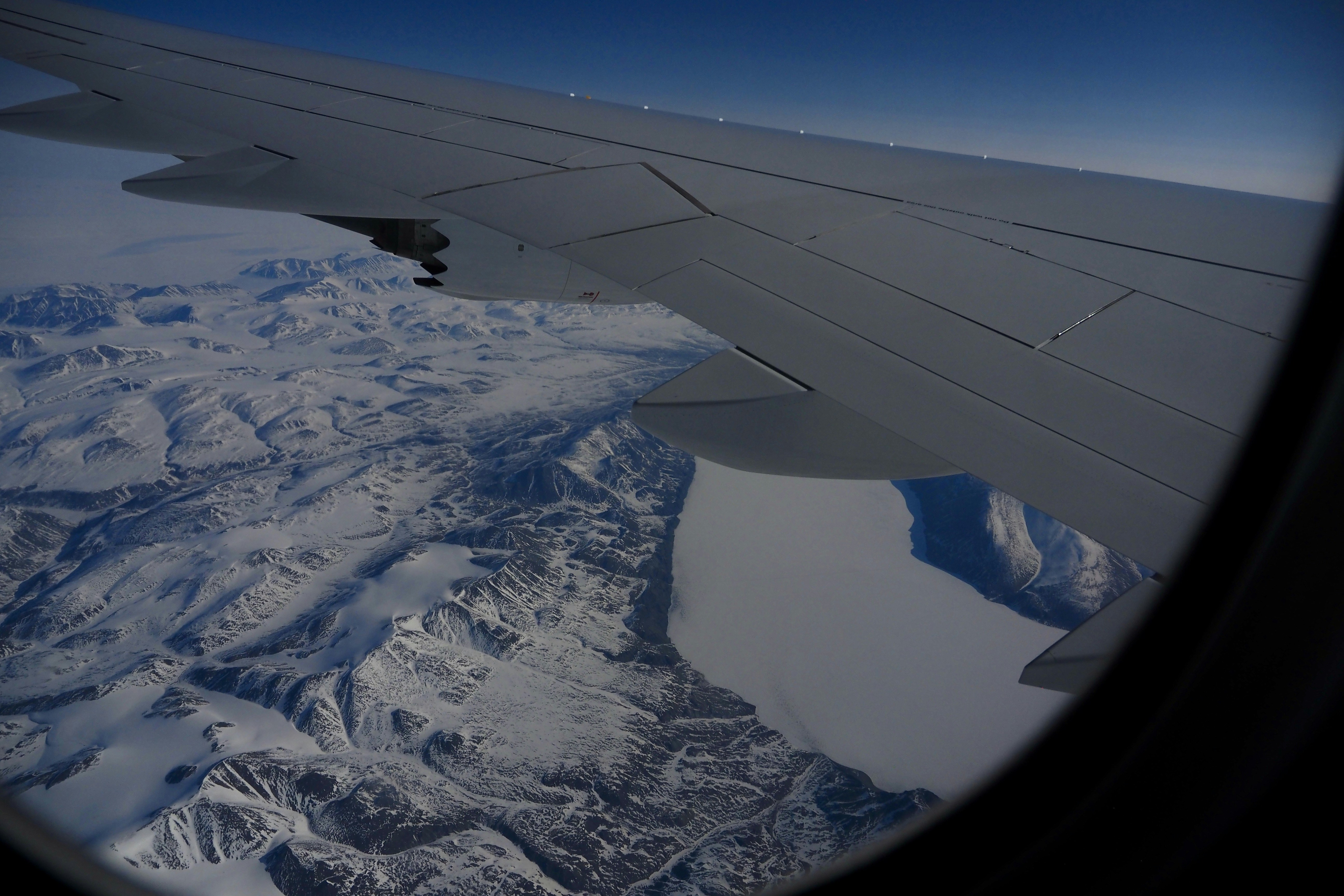 The wing of an airplane flying over a mountain range photo – Free ...