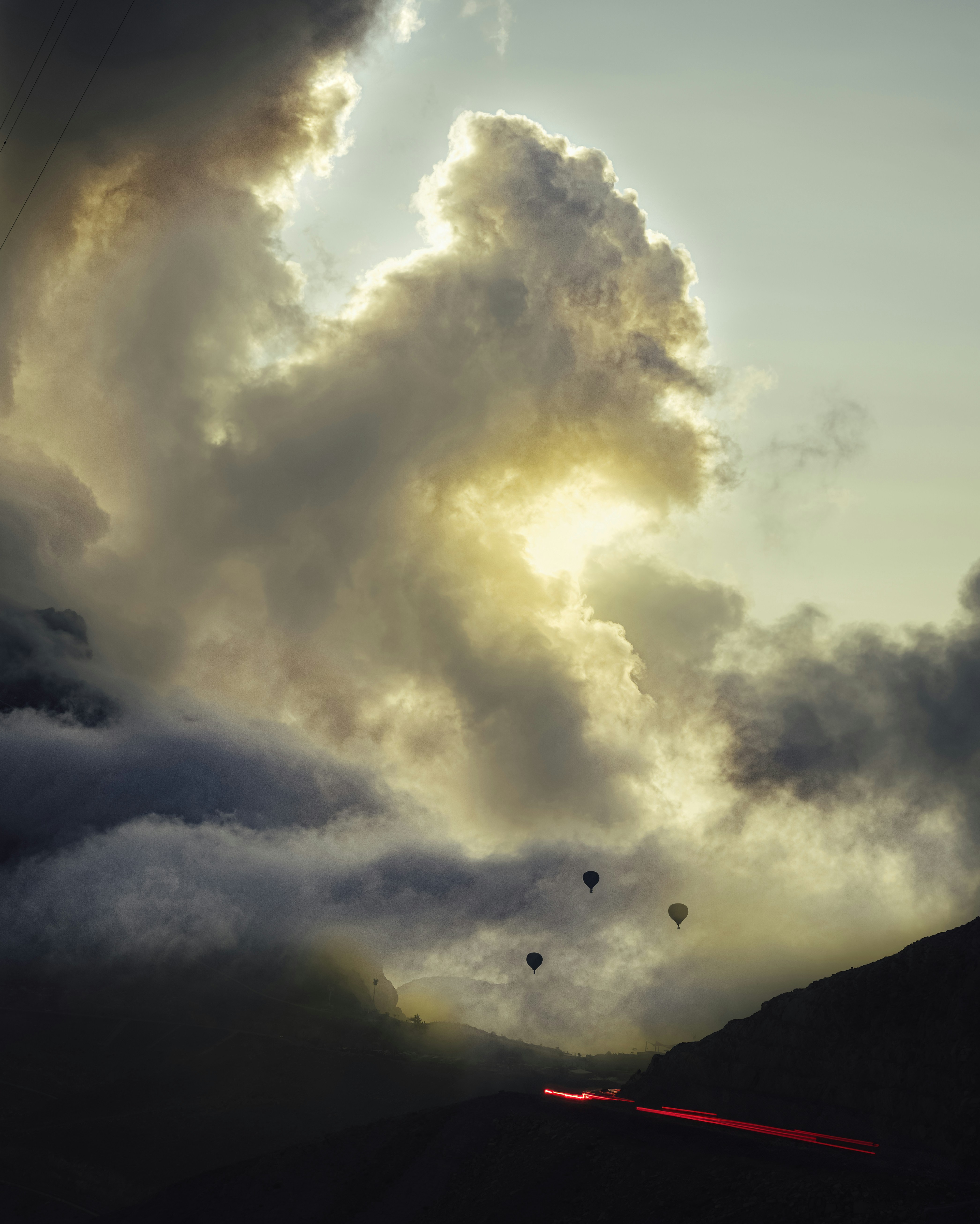 Skybound Trails: Balloons Amid Golden Clouds Above the Ridge