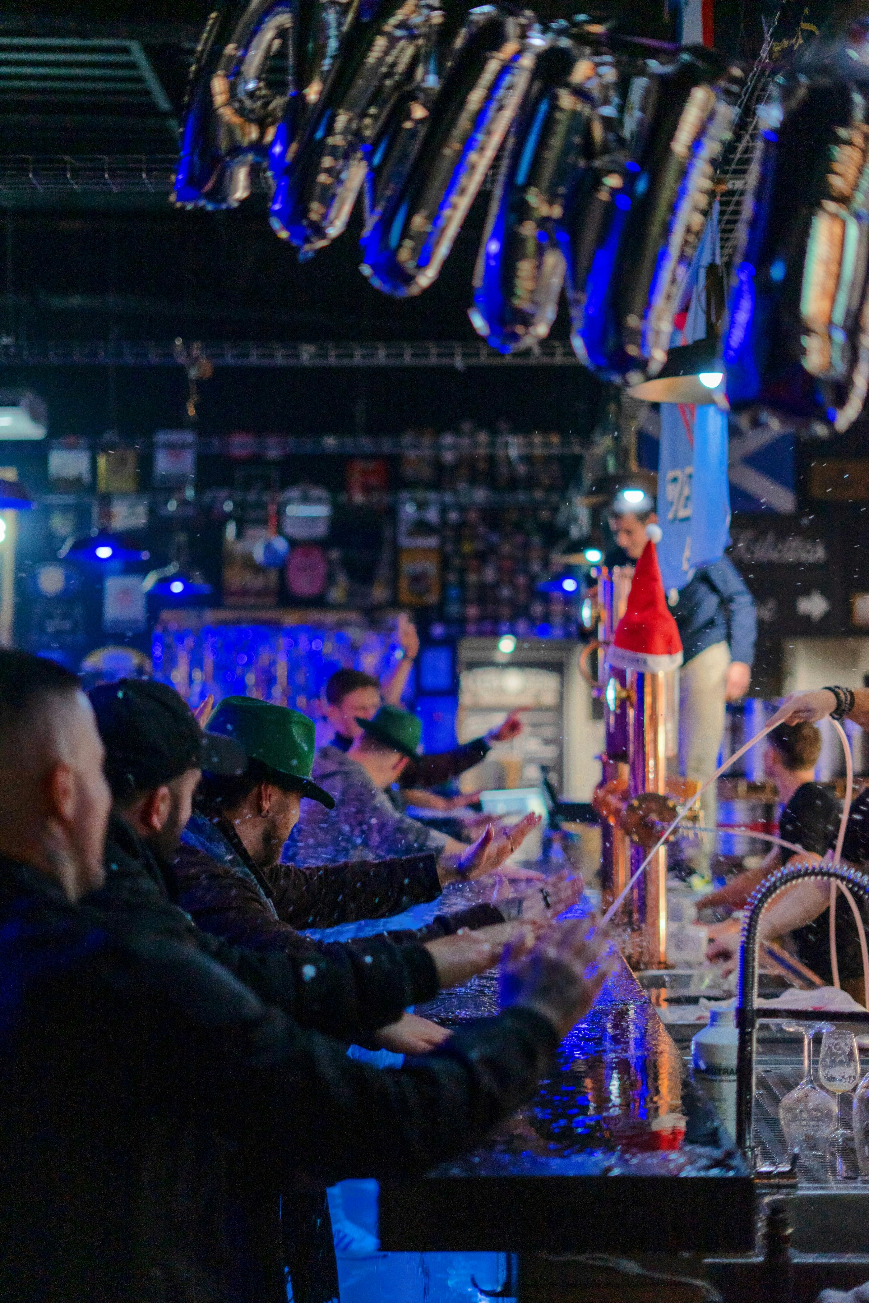 Crowd Reaches for a Festive Copper Tower at a Neon-Bar Night