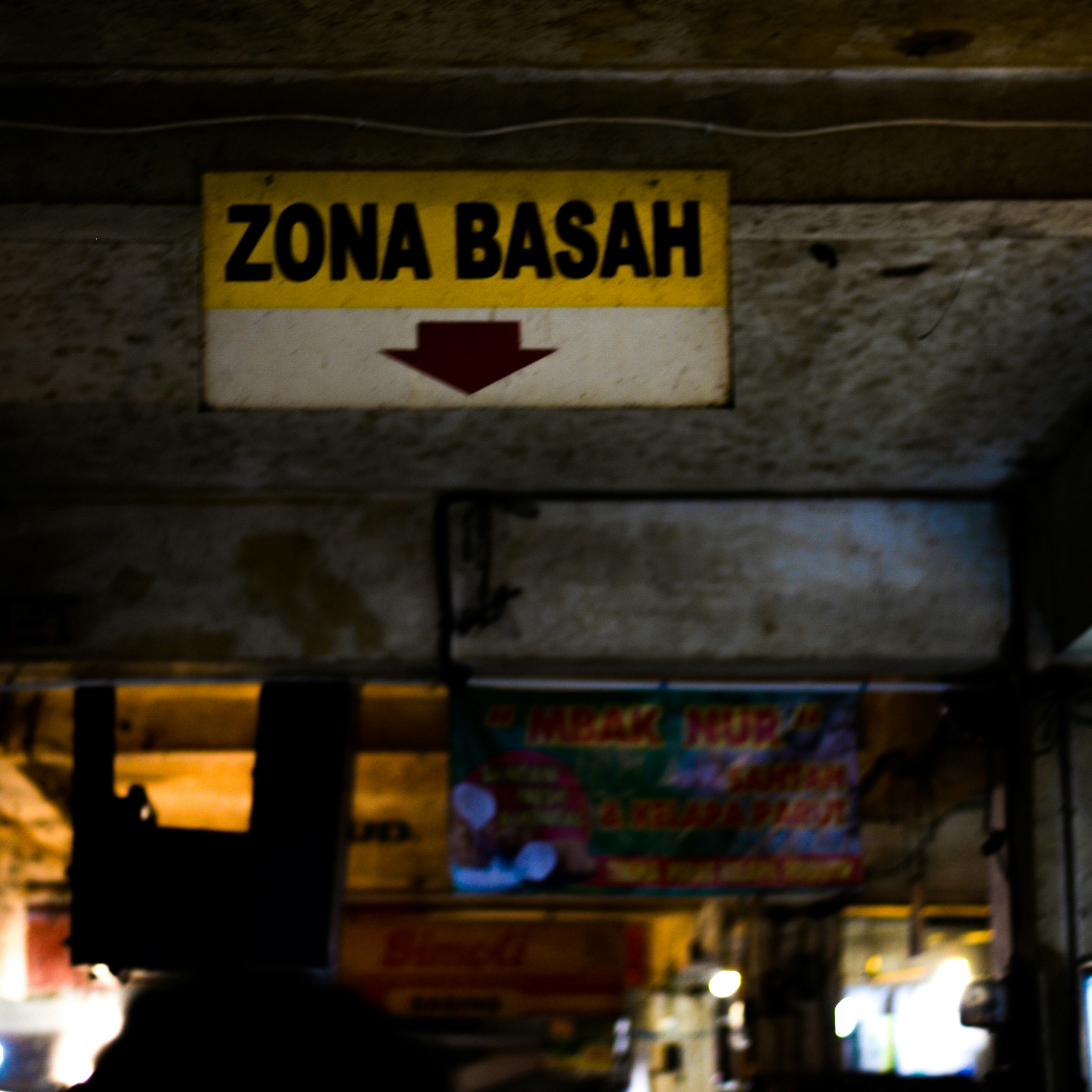 Zona Basah: Water Zone Sign Illuminates a Dim Market Corridor