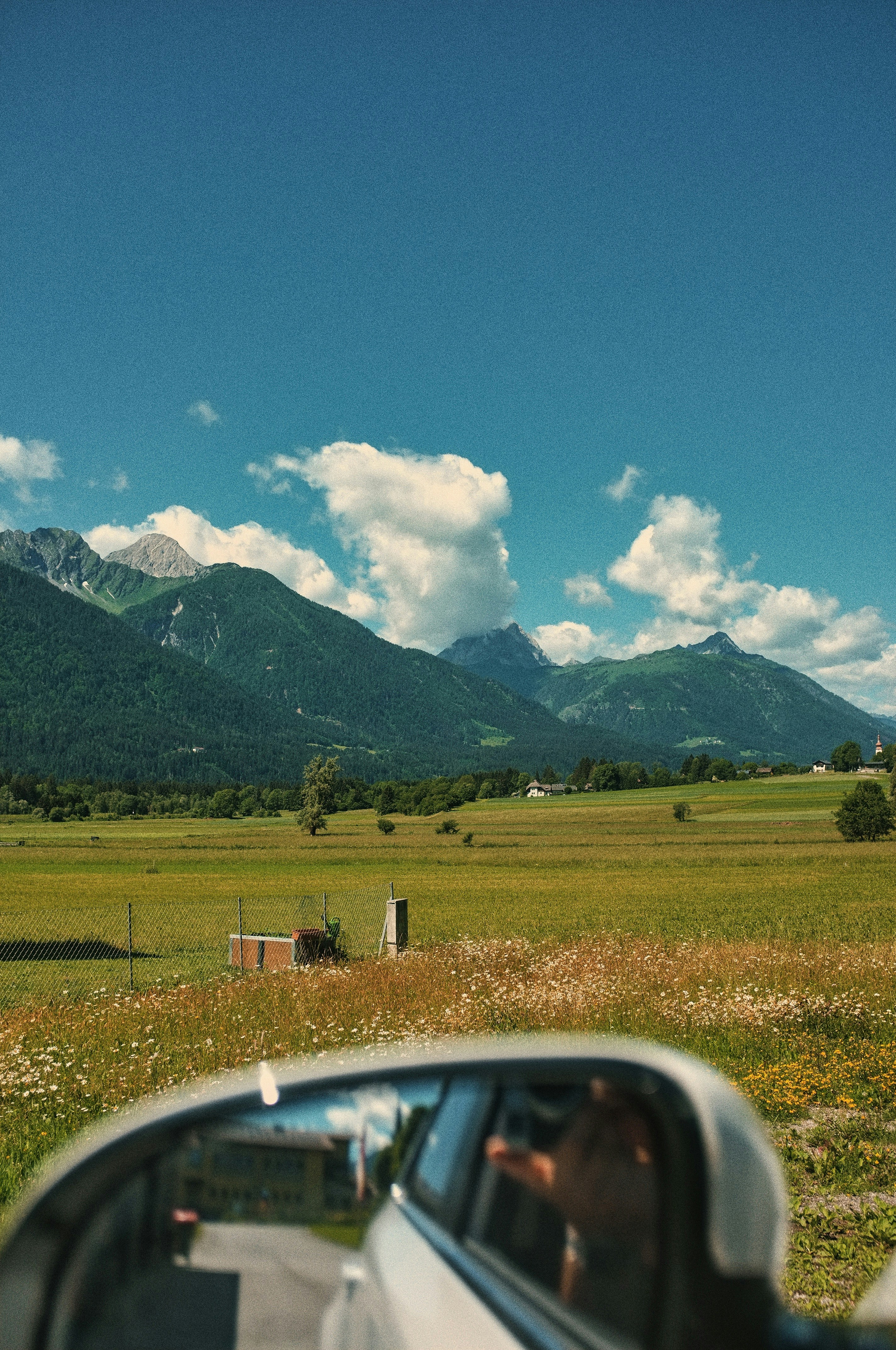 Alpine Meadow Under a Sky of Clouds, Reflected in a Car's Side Mirror