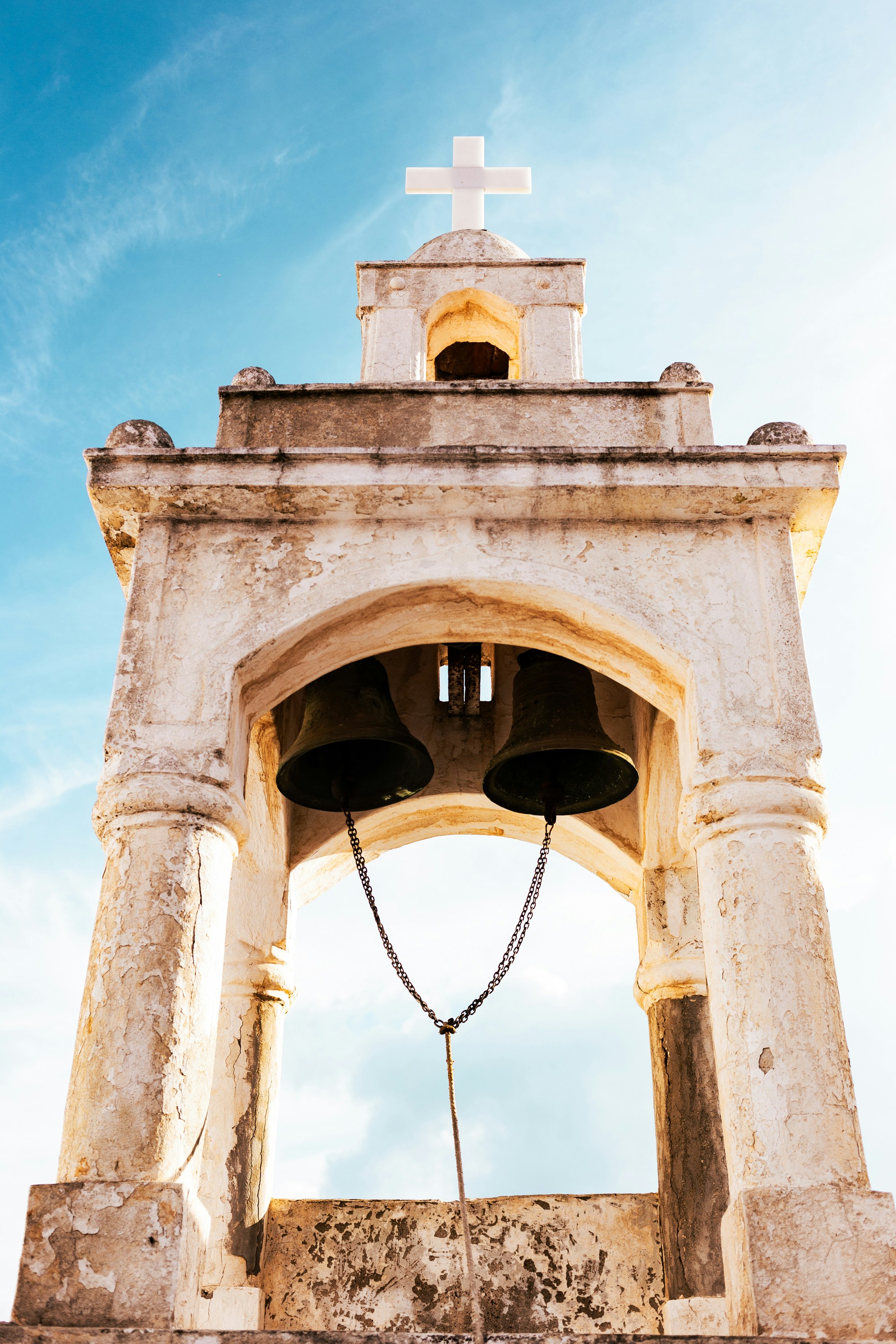 Cross at the Crest: Sunlit Bell Tower Against a Crisp Blue Sky