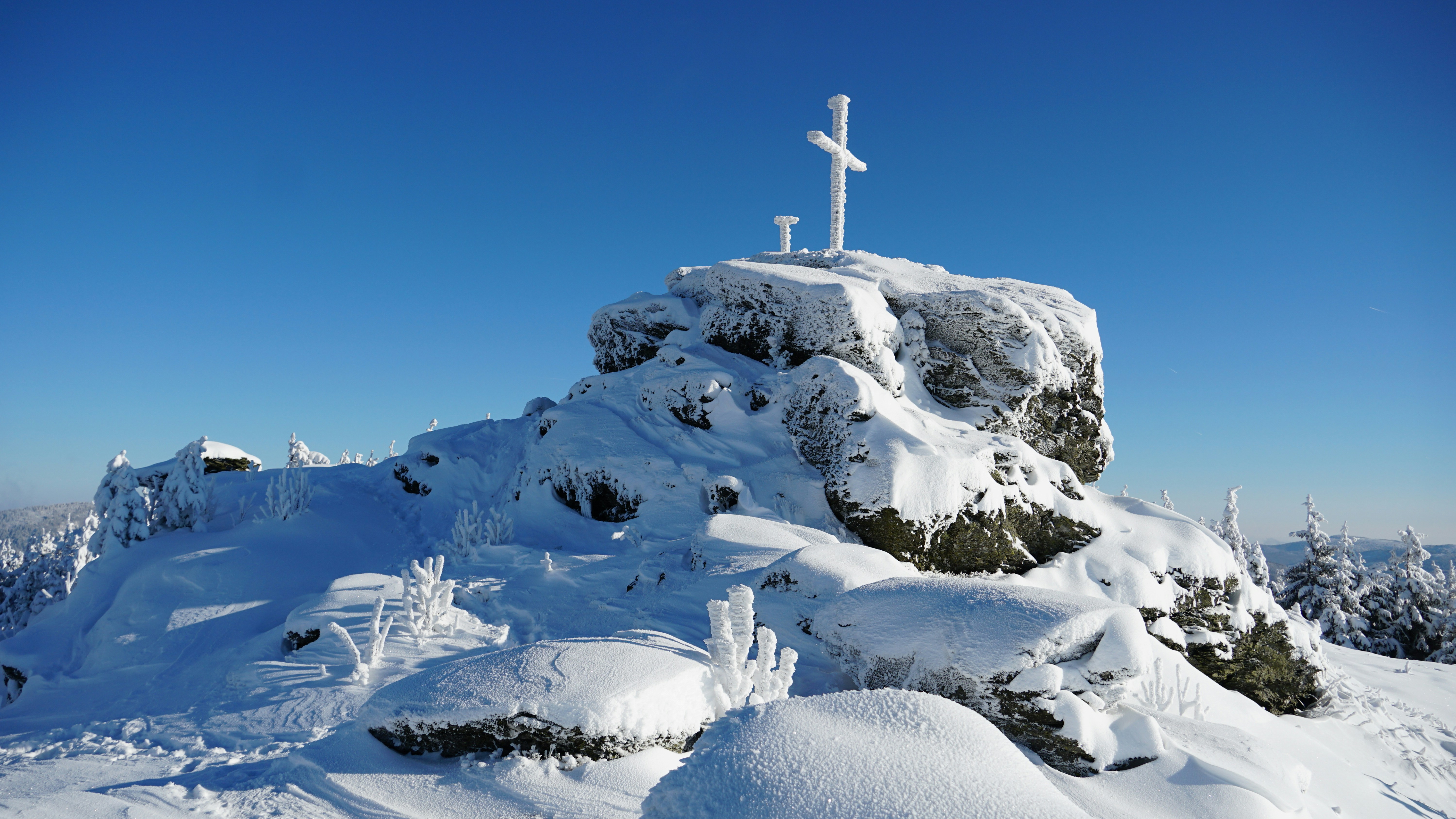 Cross on a Snow-Crowned Summit Beneath a Pristine Blue Sky