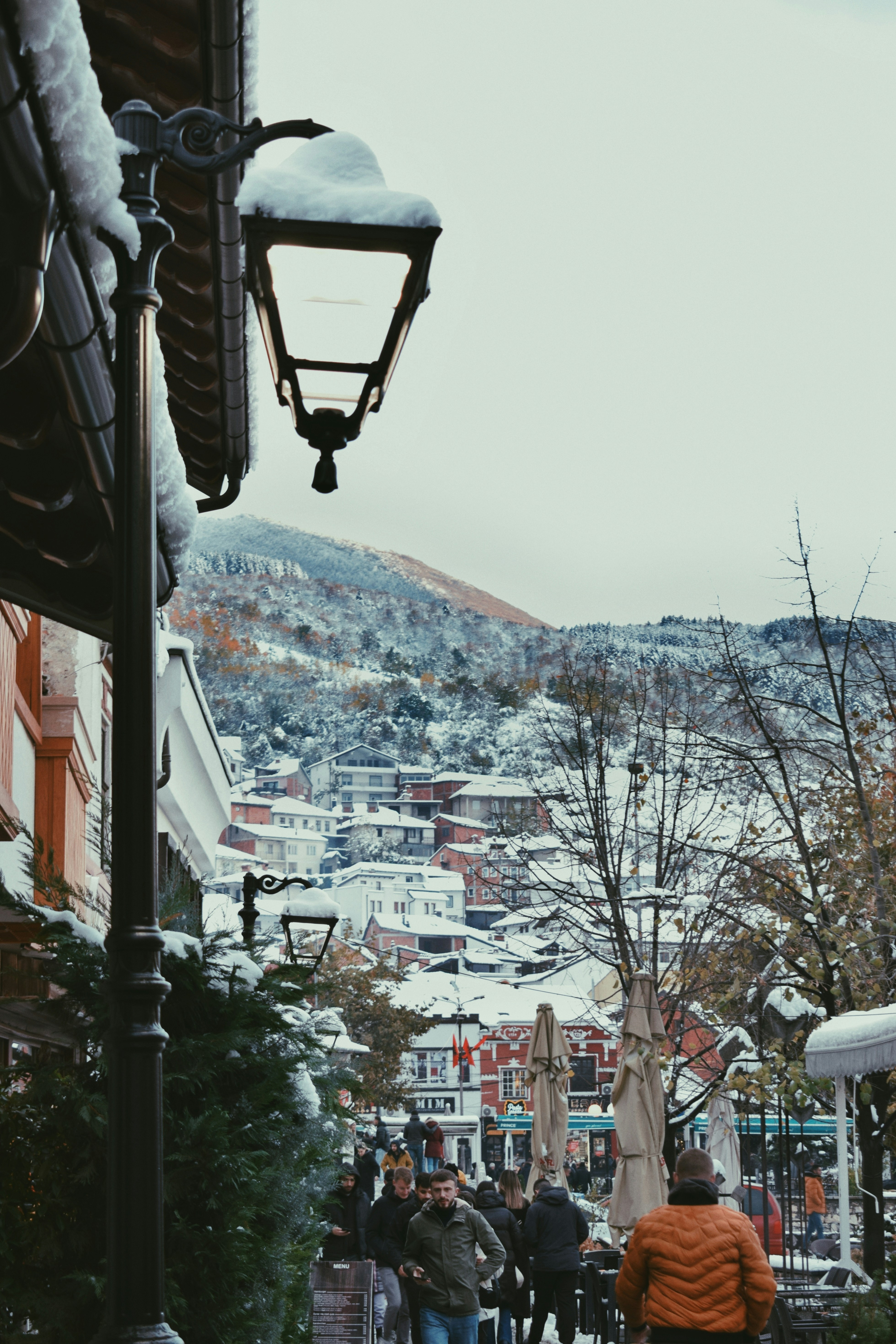 Orange Coat on a Snow-Blanketed Village Promenade Under Lanterns