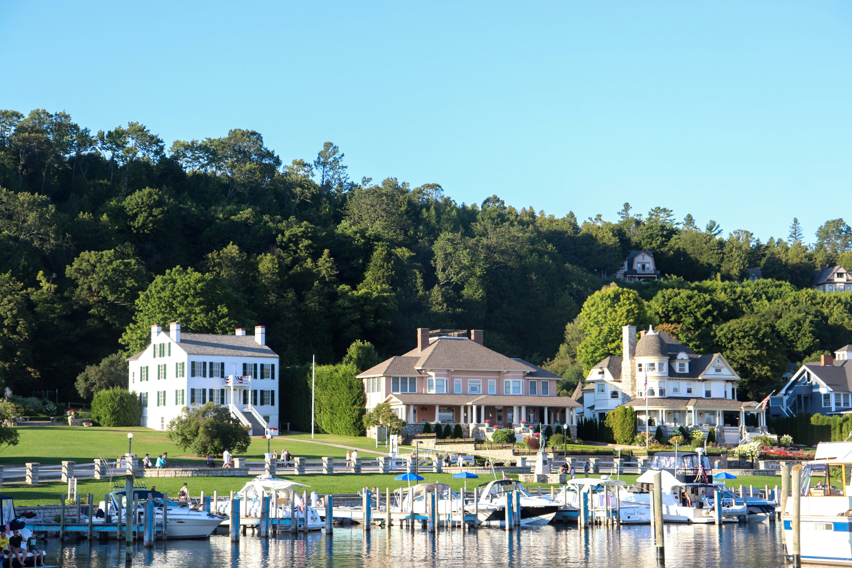 Charming lakeside homes nestled among lush greenery, reflecting in tranquil waters. Boating docks and a serene atmosphere invite relaxation.