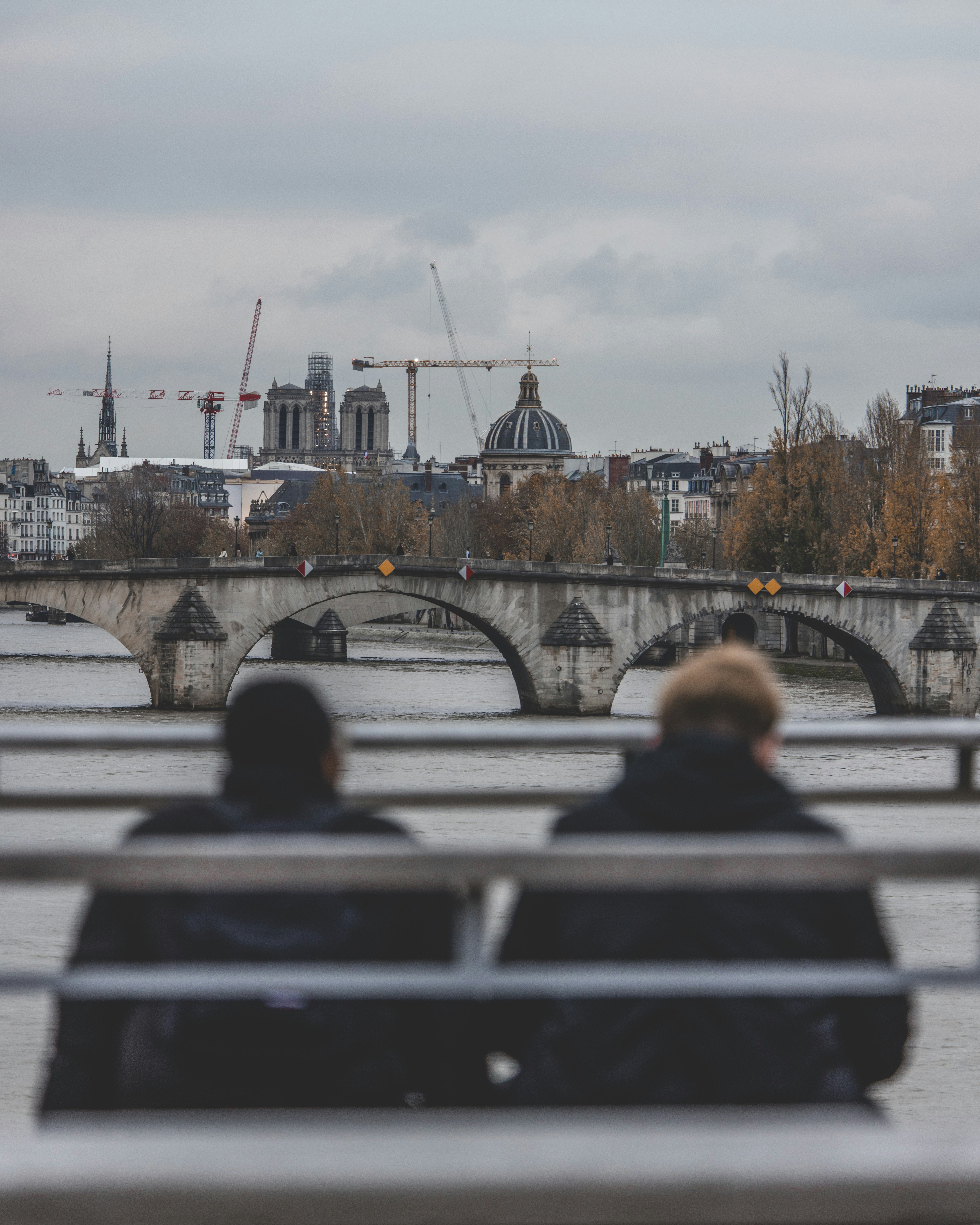 Two people sitting on a bench looking at a bridge photo – Free Grey ...