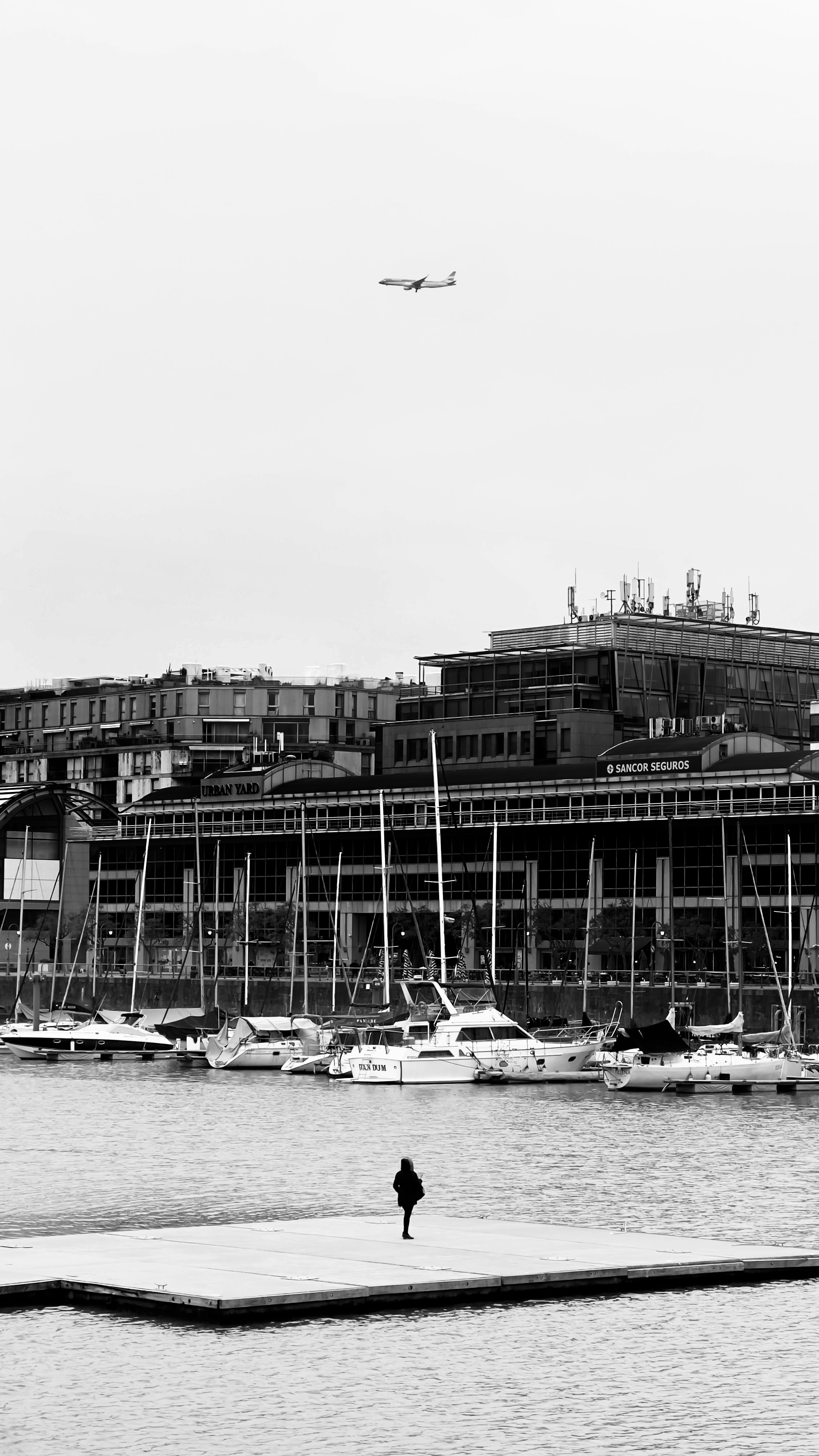 Solitary Figure at the Edge of a Monochrome Marina