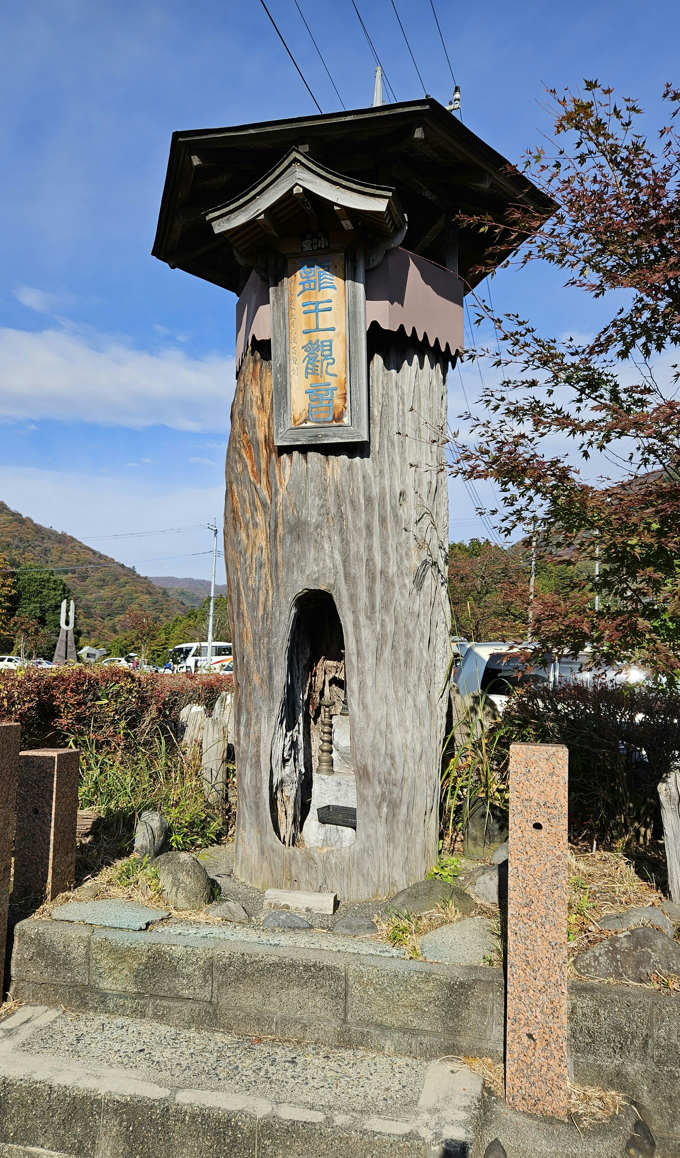 Weathered Timber Shrine Pillar with Curved Roof Amid Autumn Park