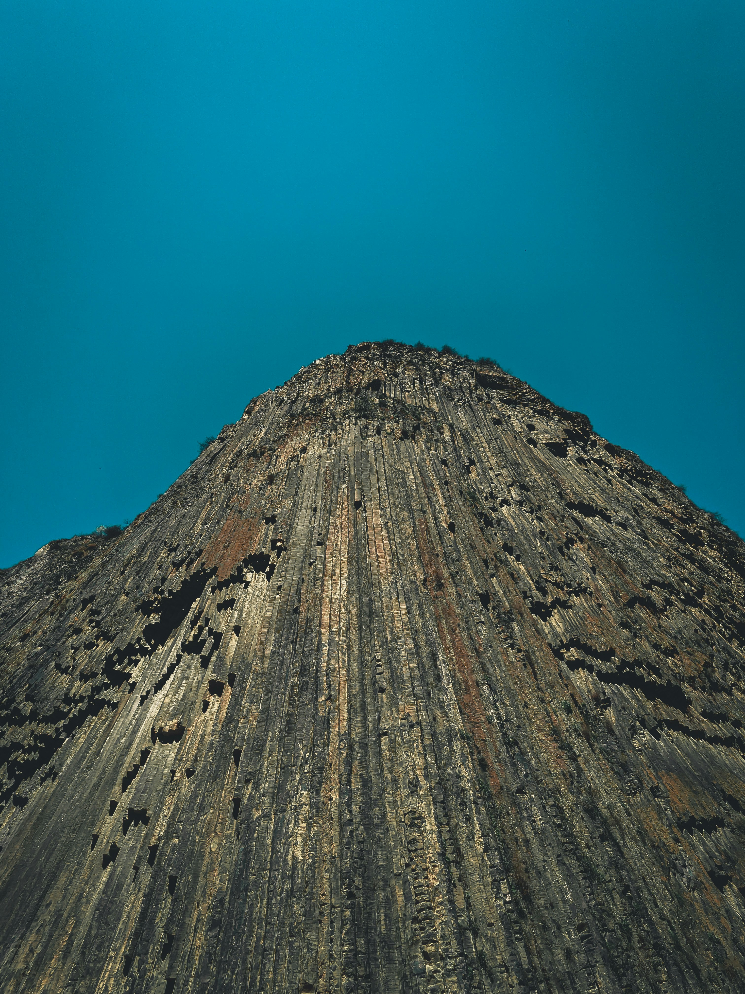 A very tall rock formation with a blue sky in the background photo ...