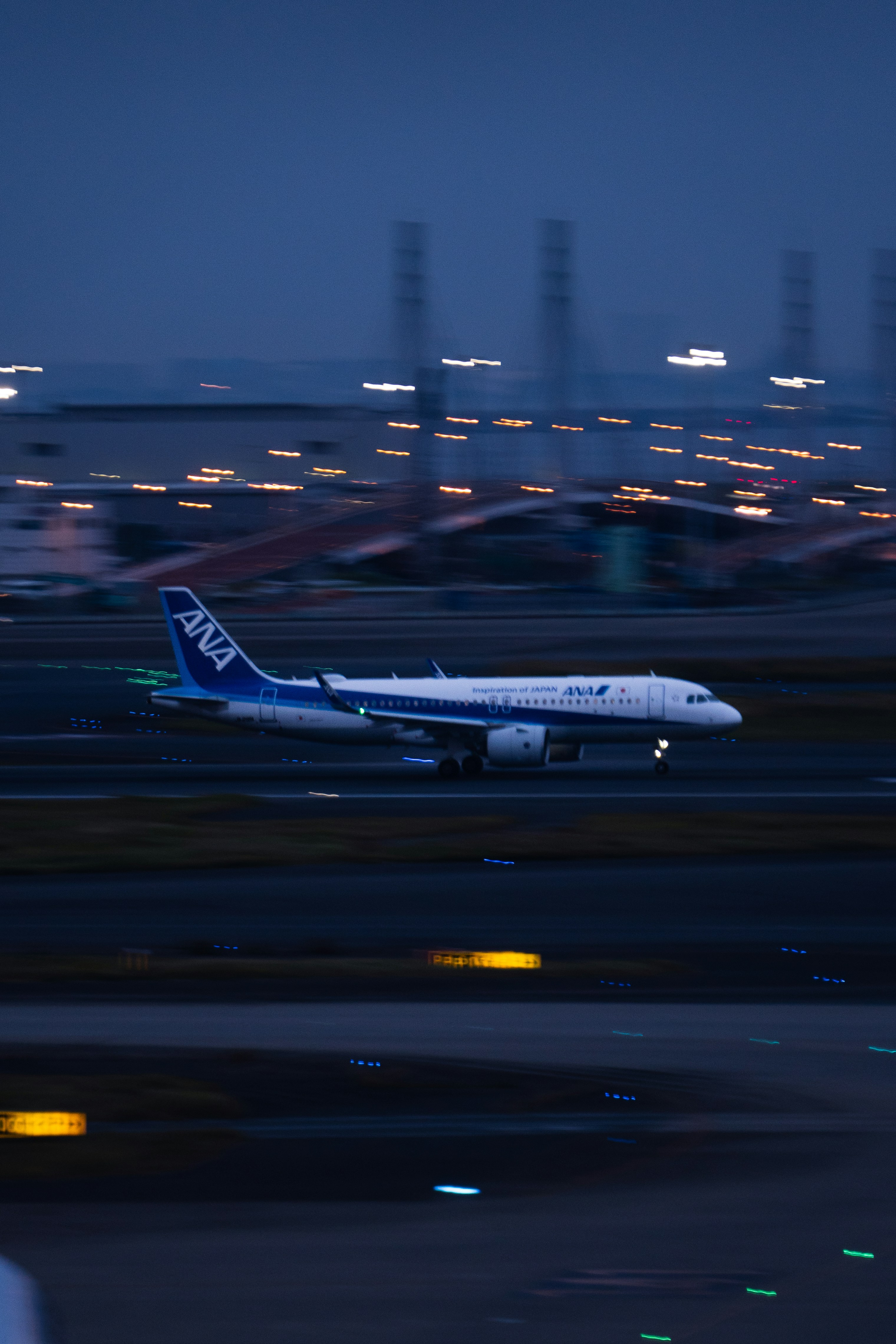 Blue-hour Takeoff Blur: ANA jet slices through airport lights