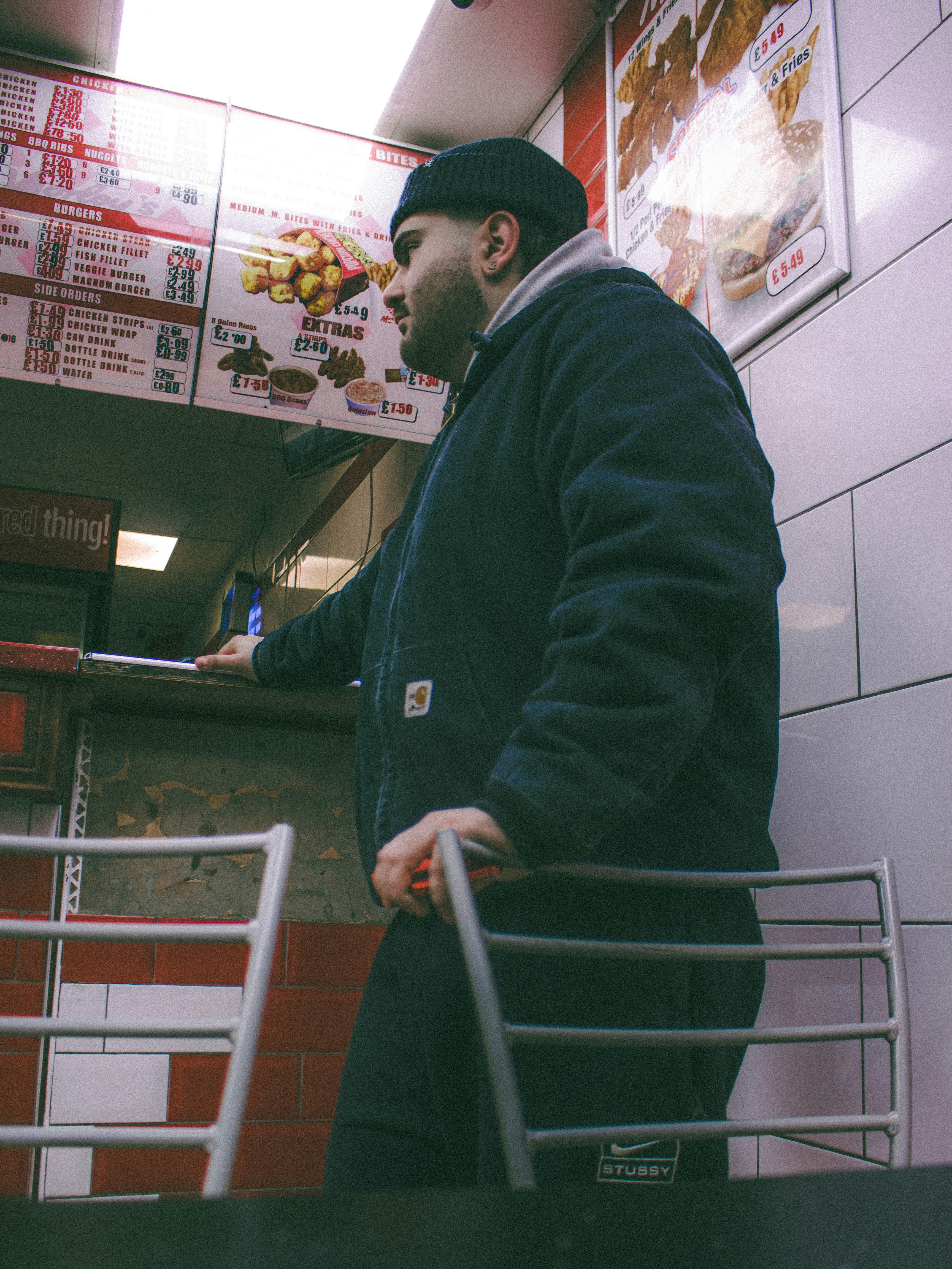 Inside the Quick Service Cut: A man in a navy parka waits by the menu