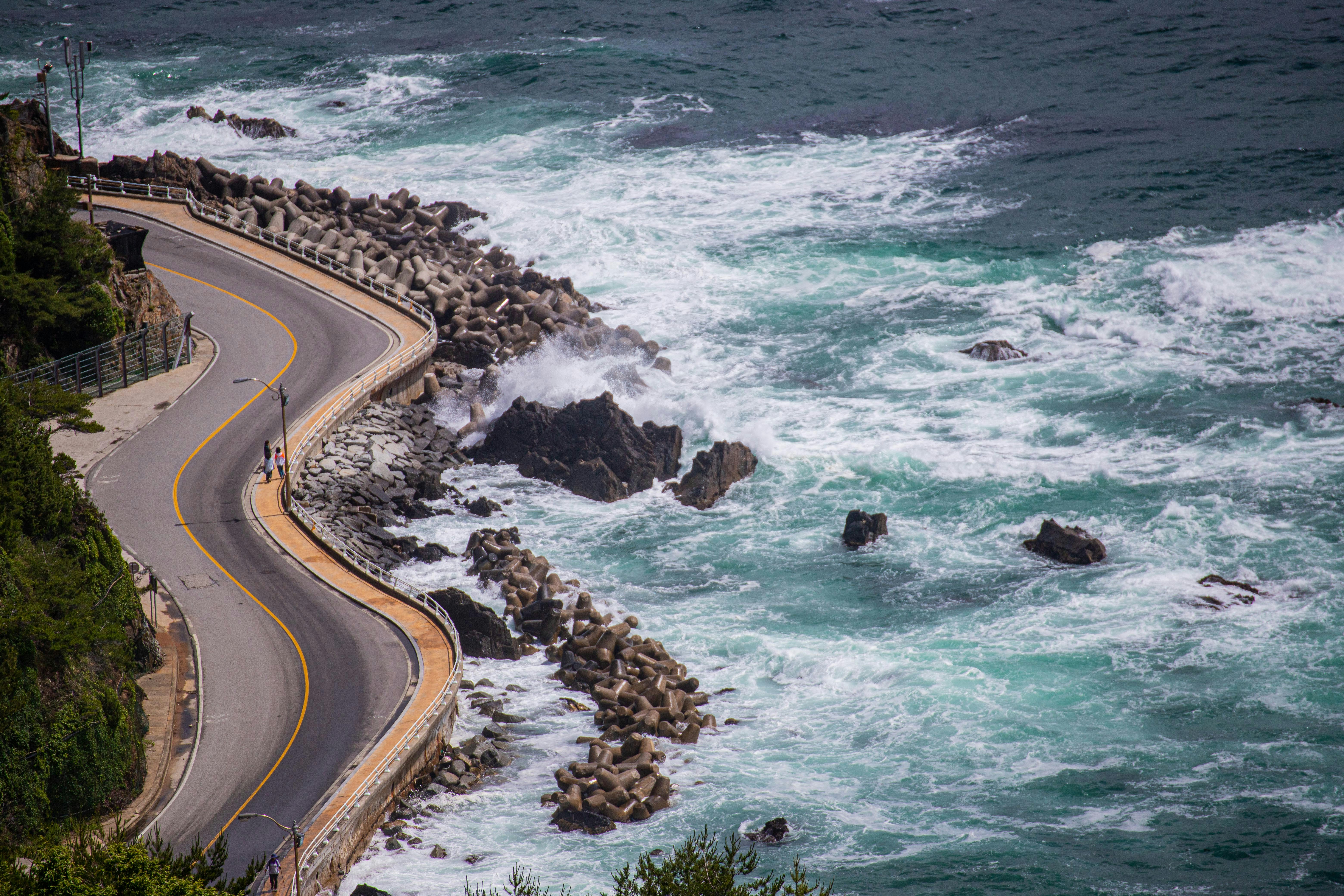 A road next to the ocean with waves crashing on it photo – Free Korea ...
