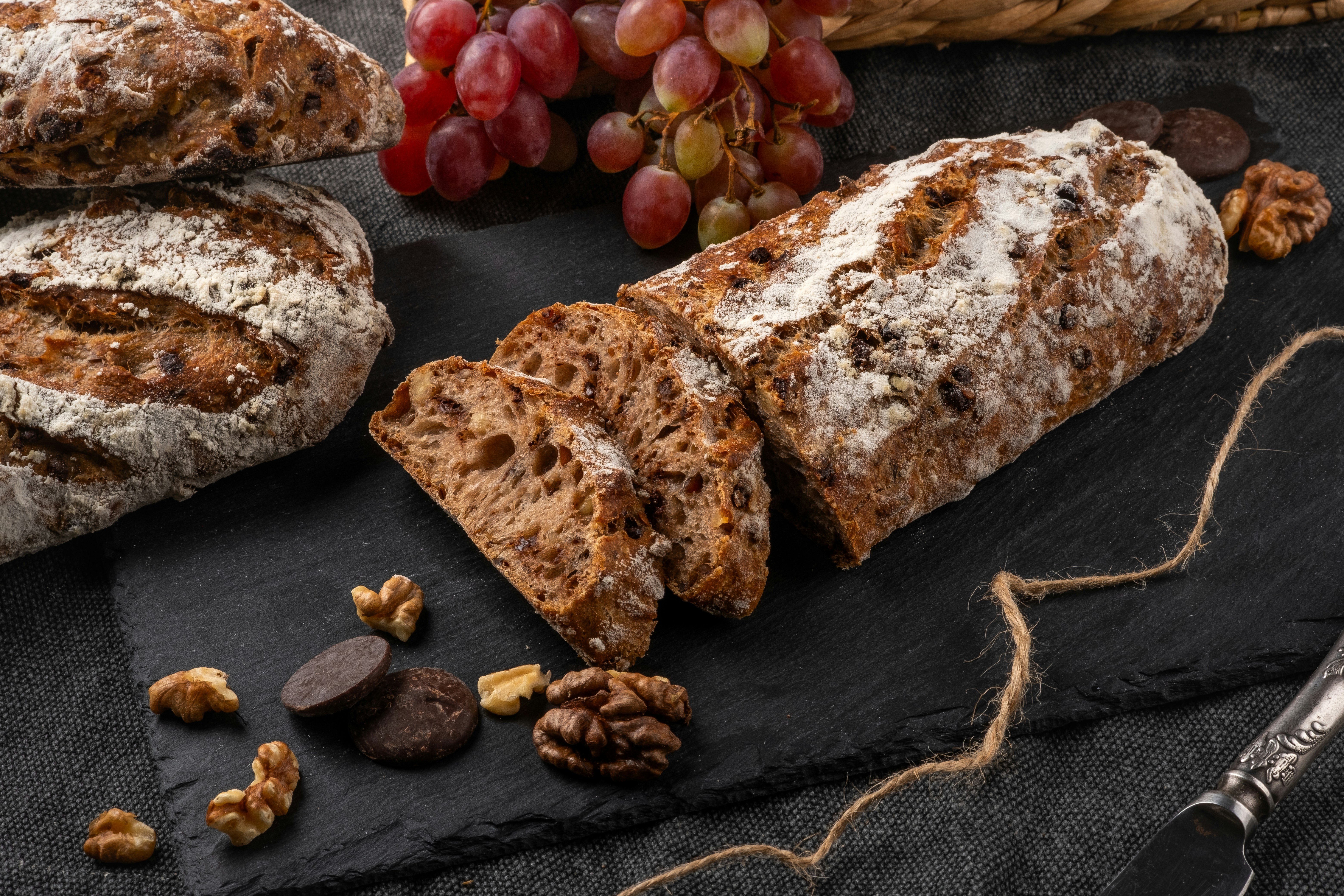 A loaf of bread, nuts, and grapes on a slate board photo – Free Moldova ...