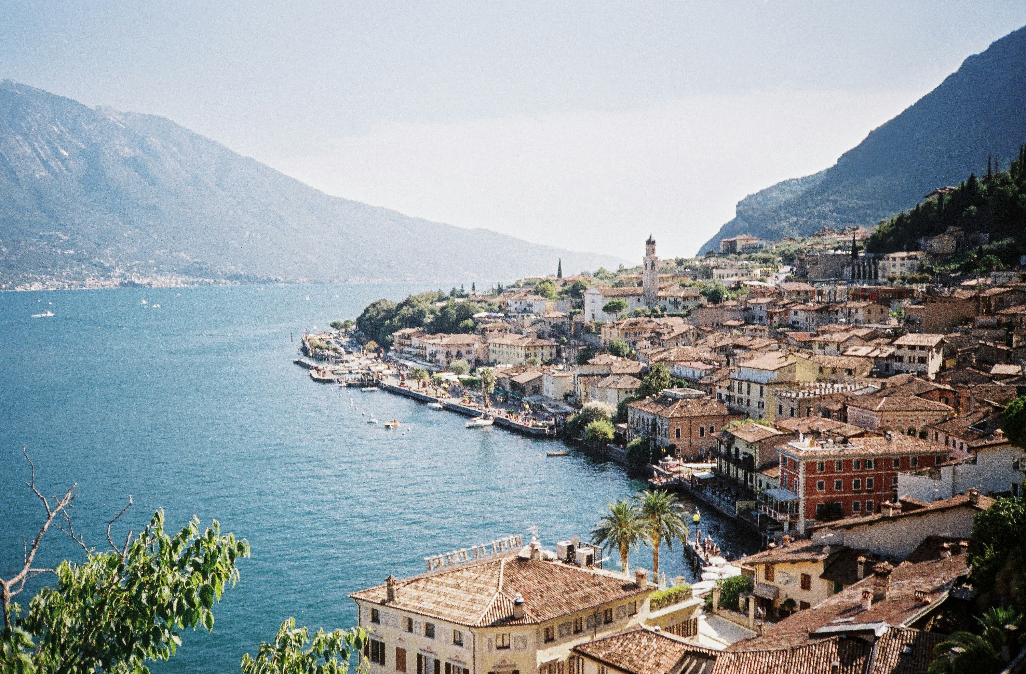 Charming village nestled along a tranquil lake with surrounding mountains under a clear sky.