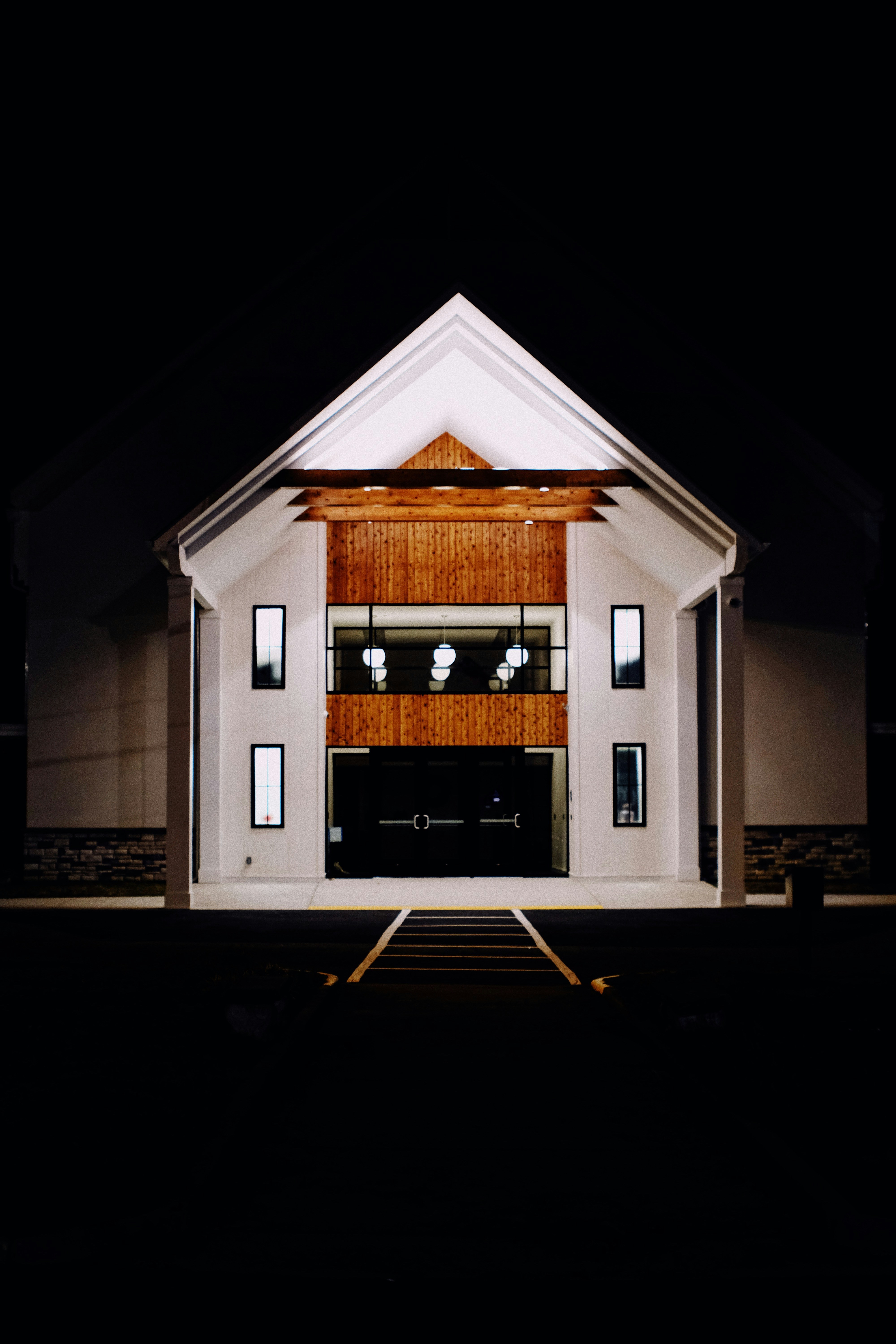 A white building with a lit up front entrance photo – Free Building ...