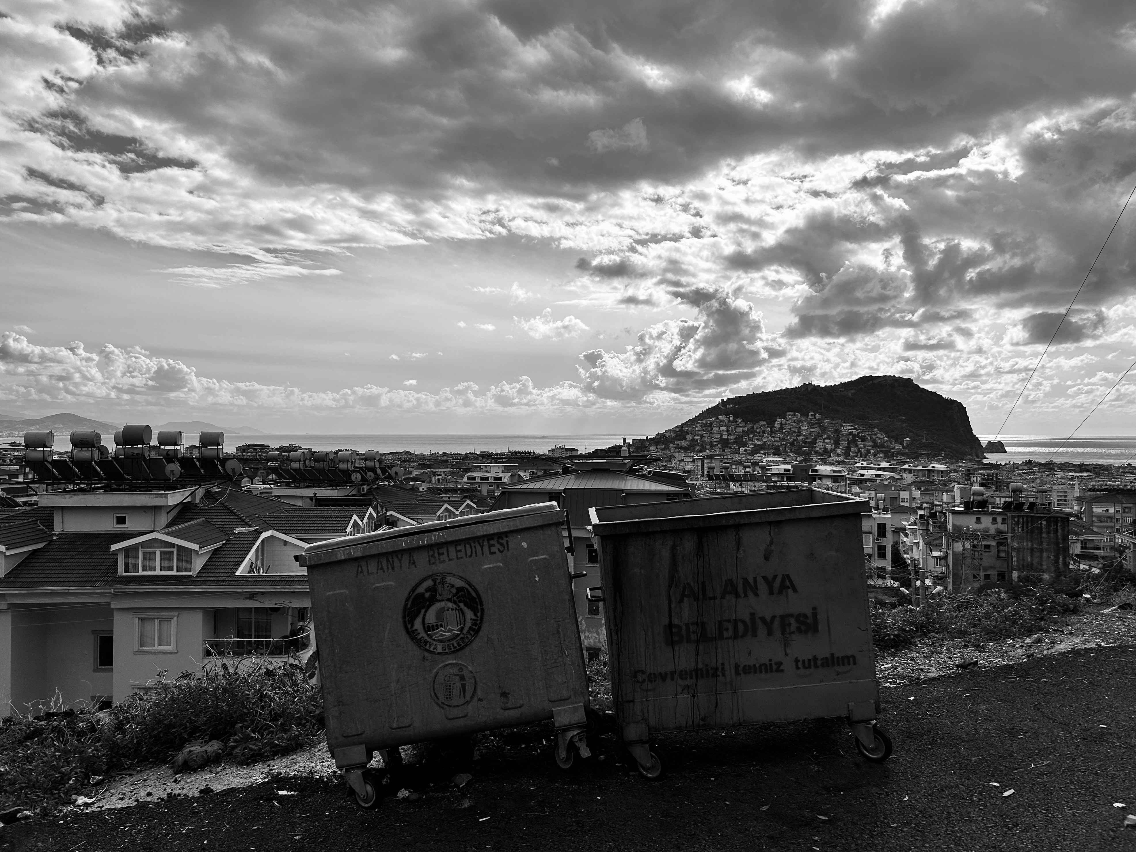 Waste Bins Between Distant Rooftops and a Prominent Hill