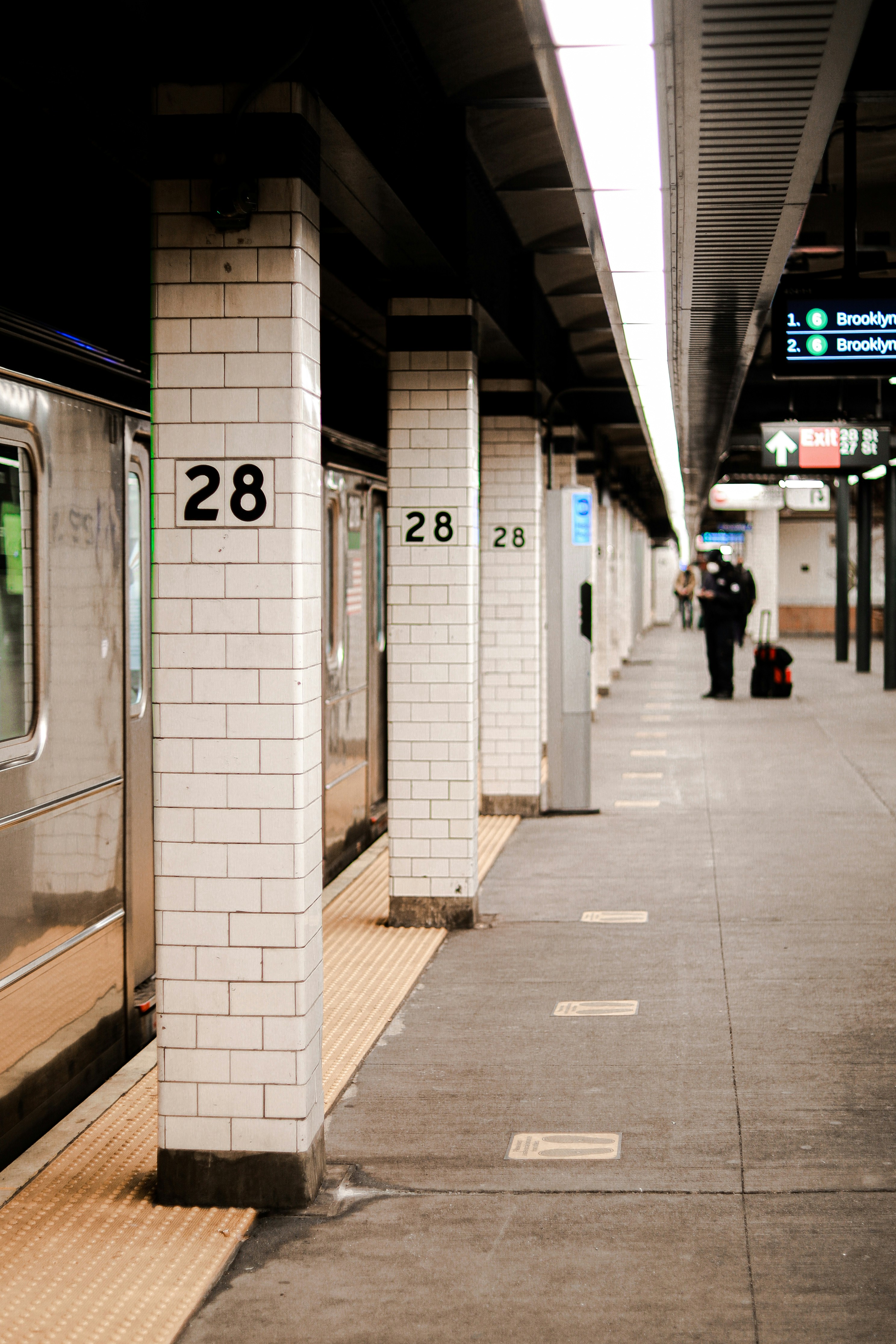Subway platform featuring numbered columns and a glimpse of a traveler waiting, capturing the essence of urban commuting.