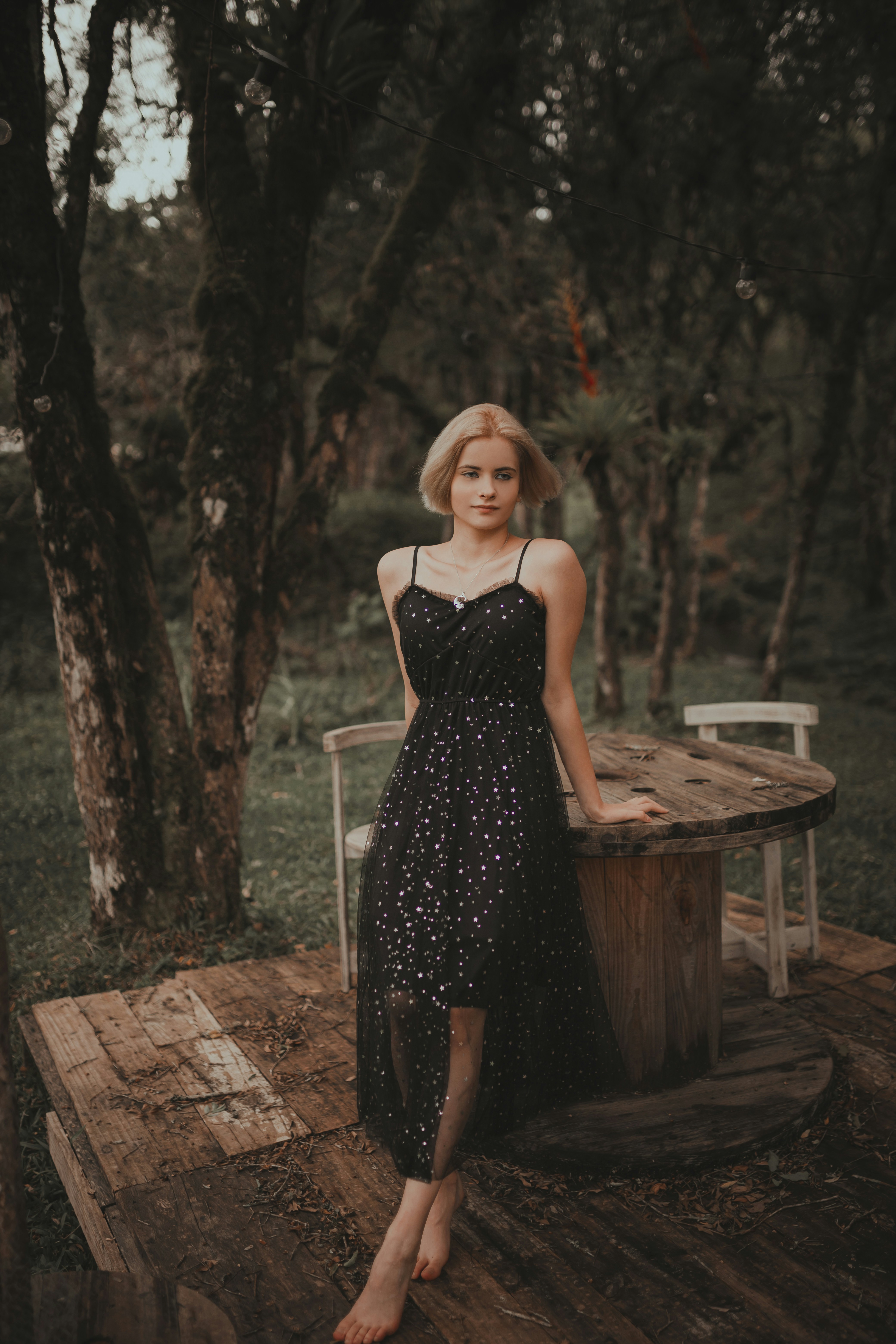 A woman in a black dress standing on a wooden platform photo – Free ...