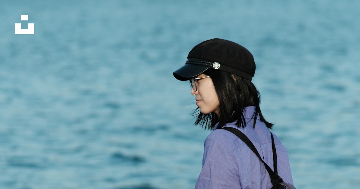 배낭을 멘 여자가 물을 바라보고 있다 사진 Unsplash의 무료 반바지 이미지