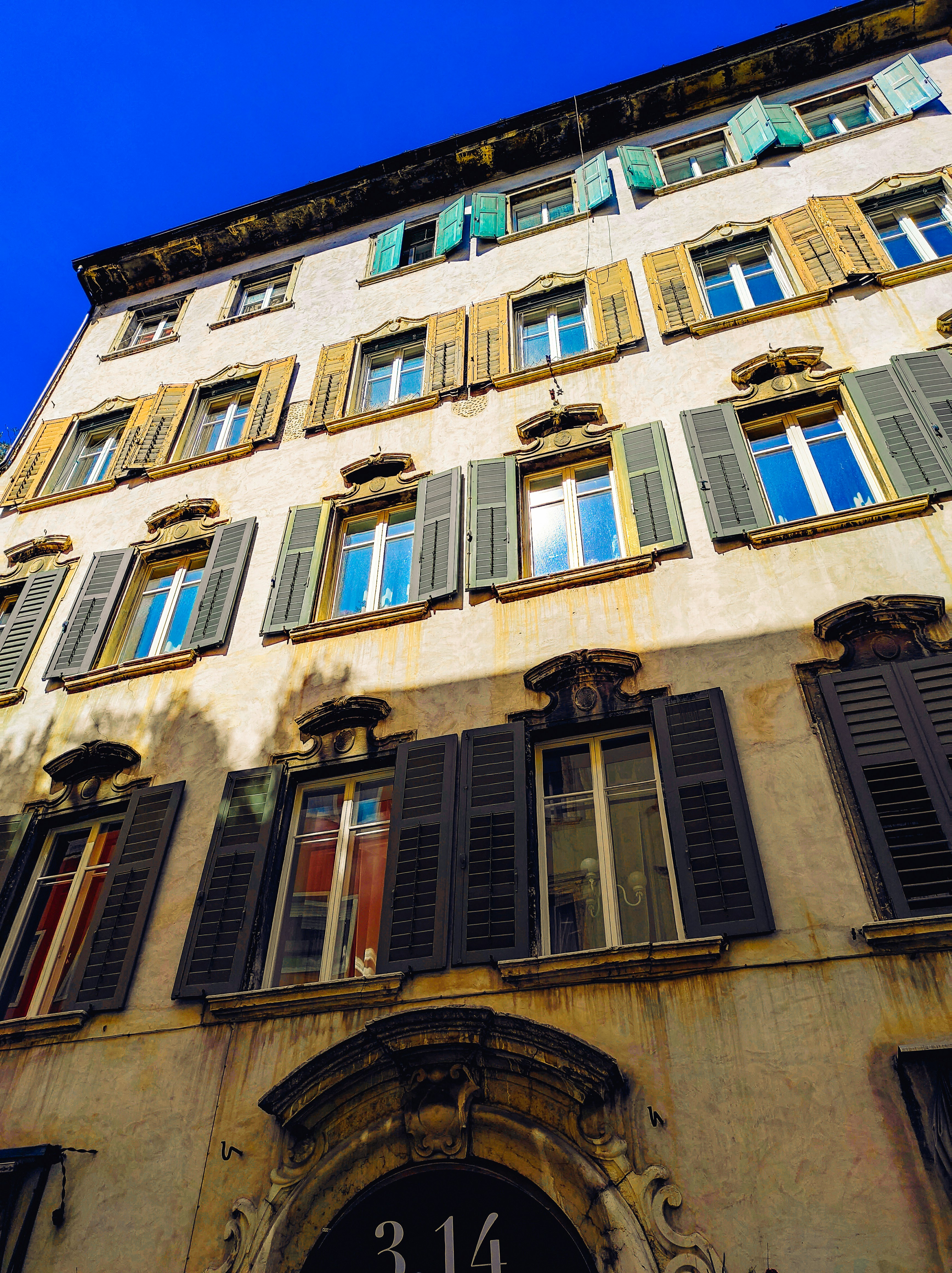 No. 314 at Noon: Sunlit Facade with Shuttered Windows and an Ornate Arch