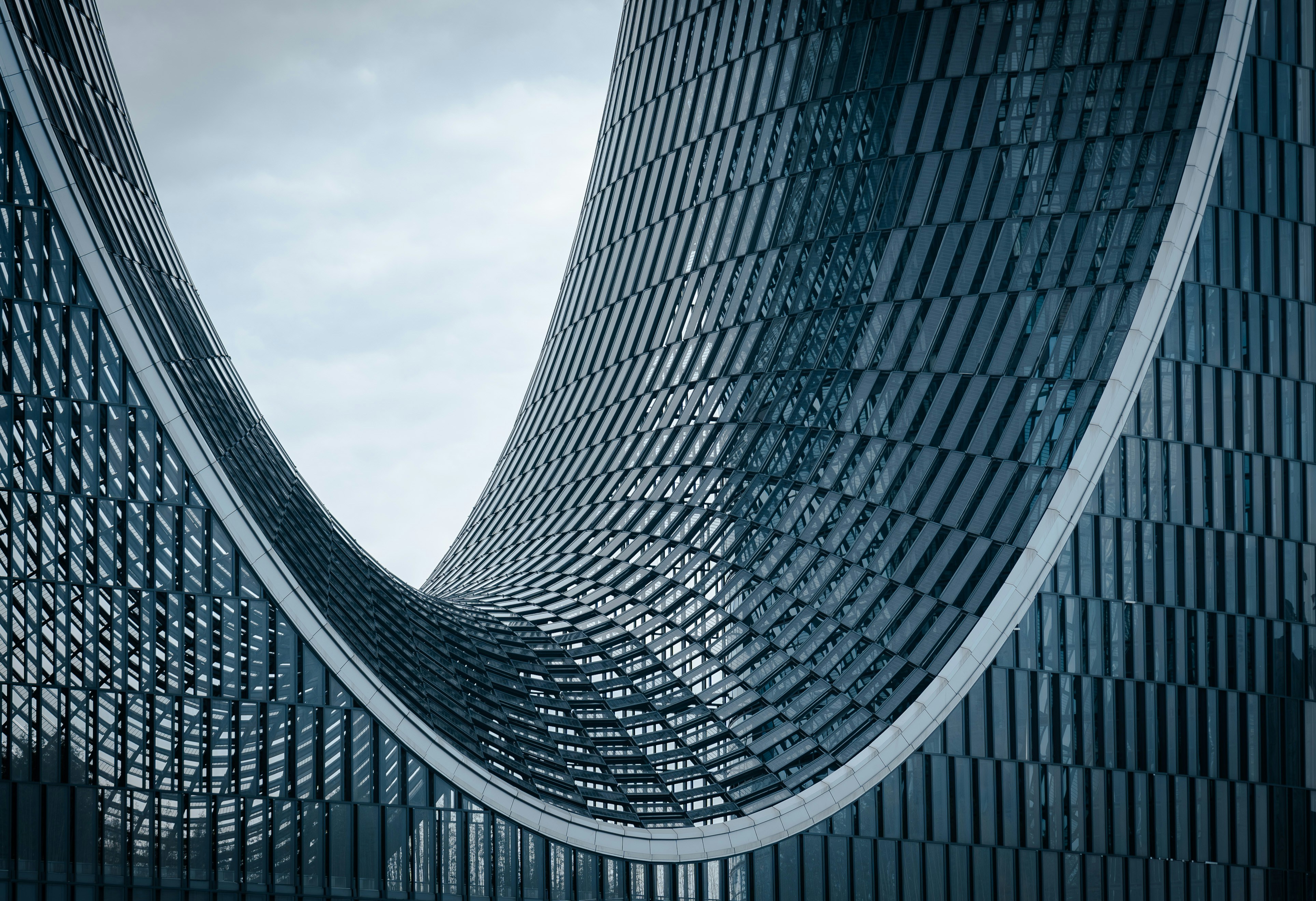 Sweeping curves of modern architectural towers against a cloudy sky.