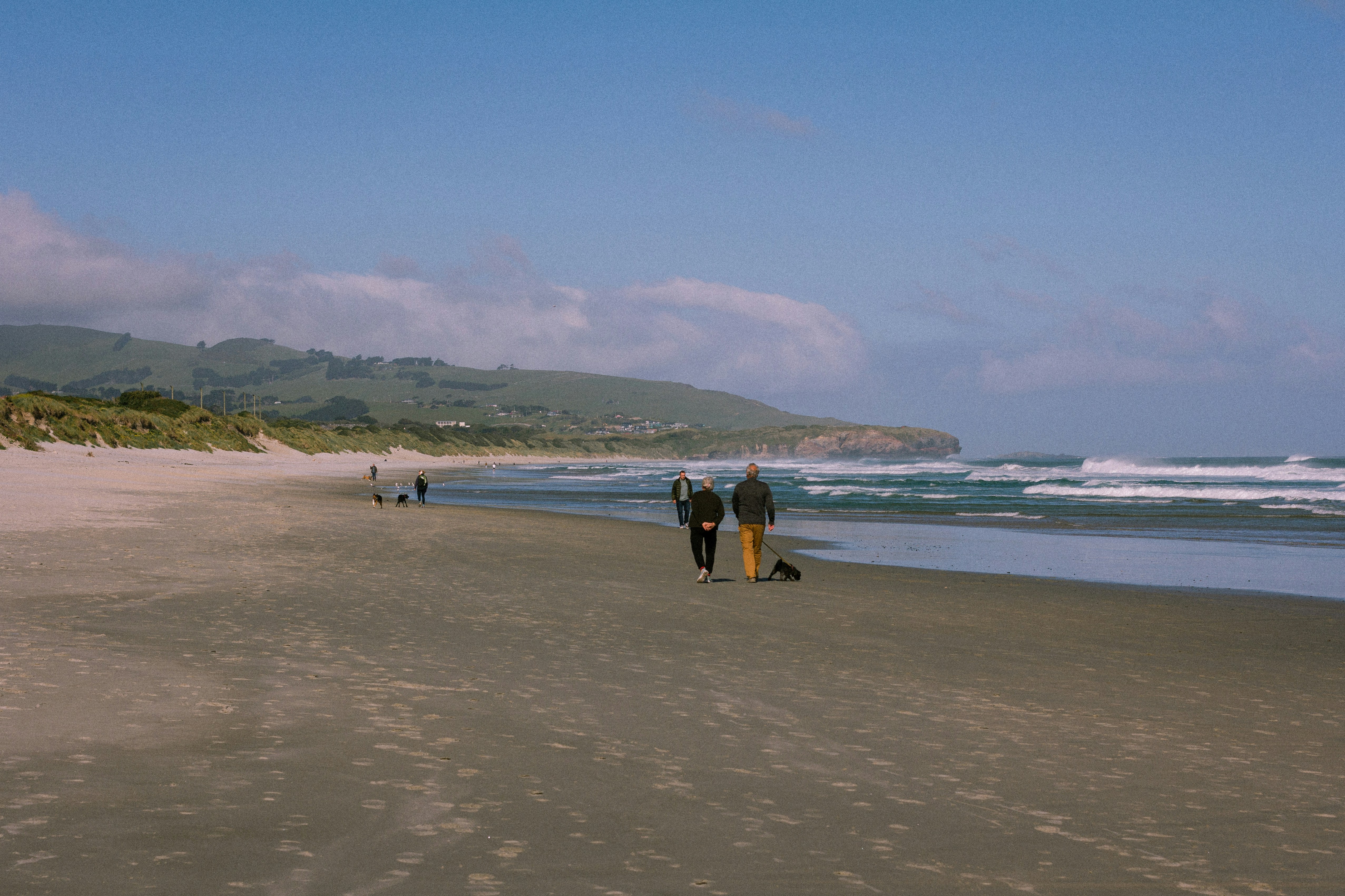 Two Figures Stroll the Quiet Dune-Lined Shore