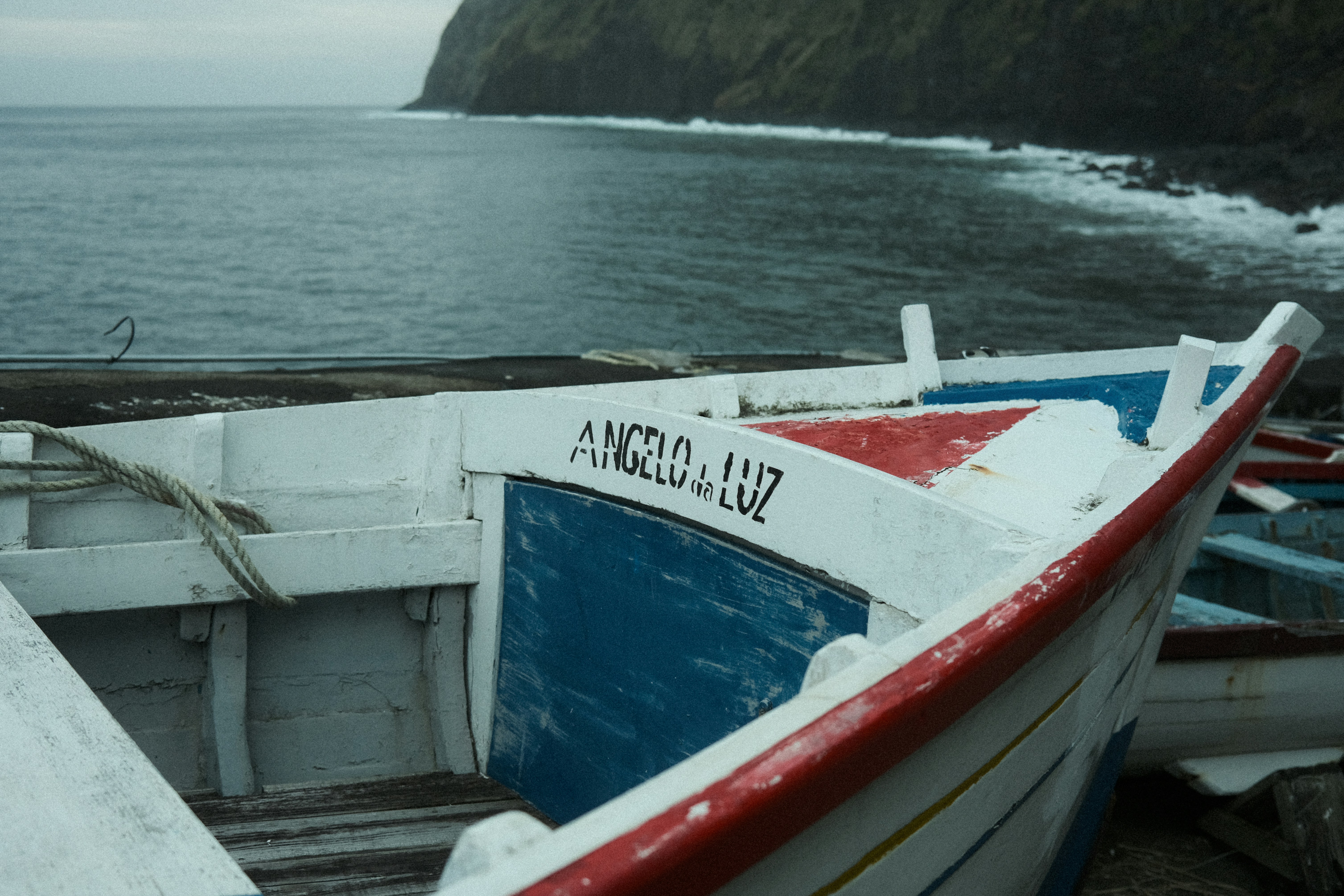 Colorful Hulls Framed by Sea Cliff: Boats at Quiet Shore
