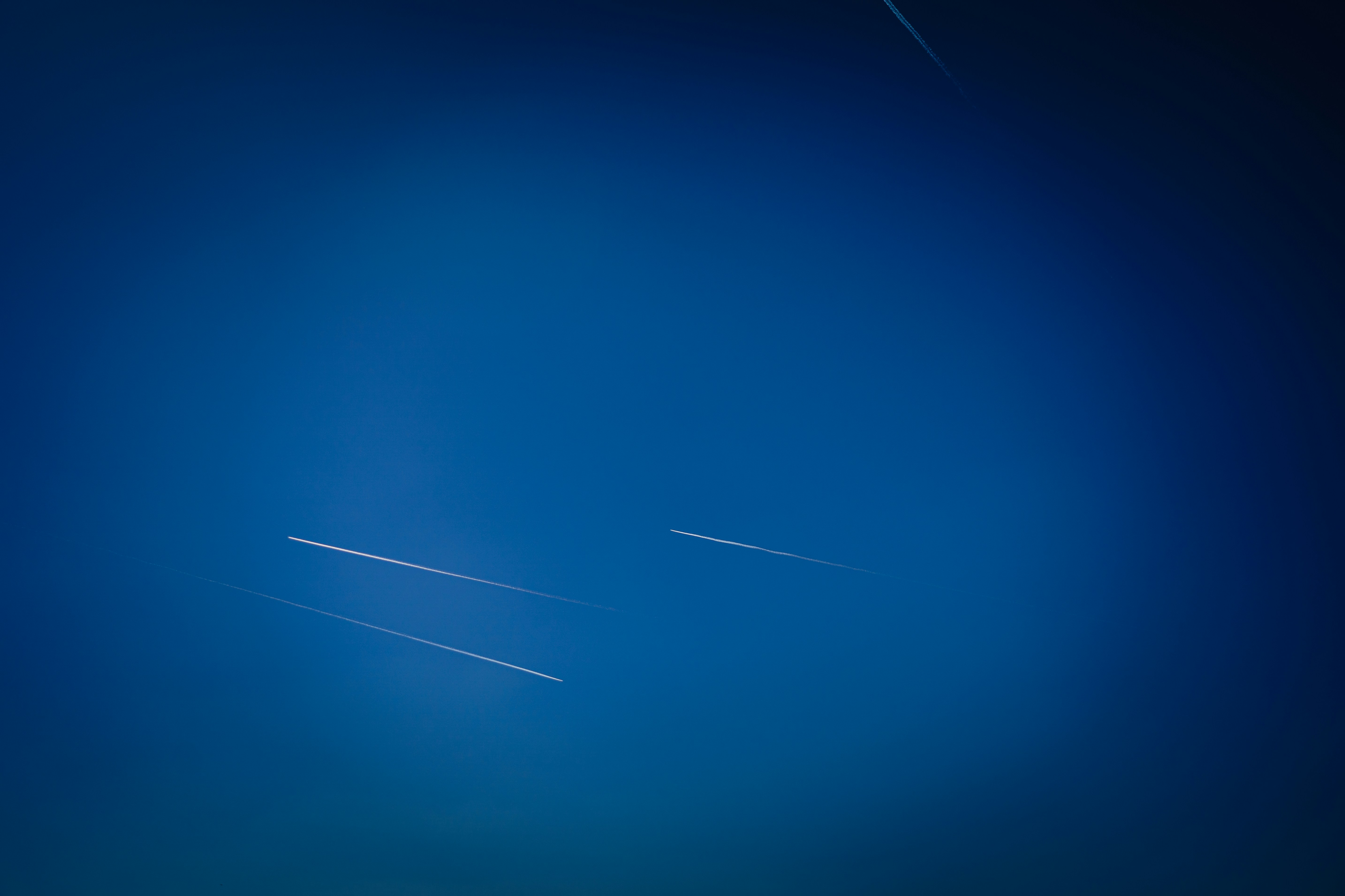 Contrails streak across a deep blue sky, casting a serene and minimalistic scene.